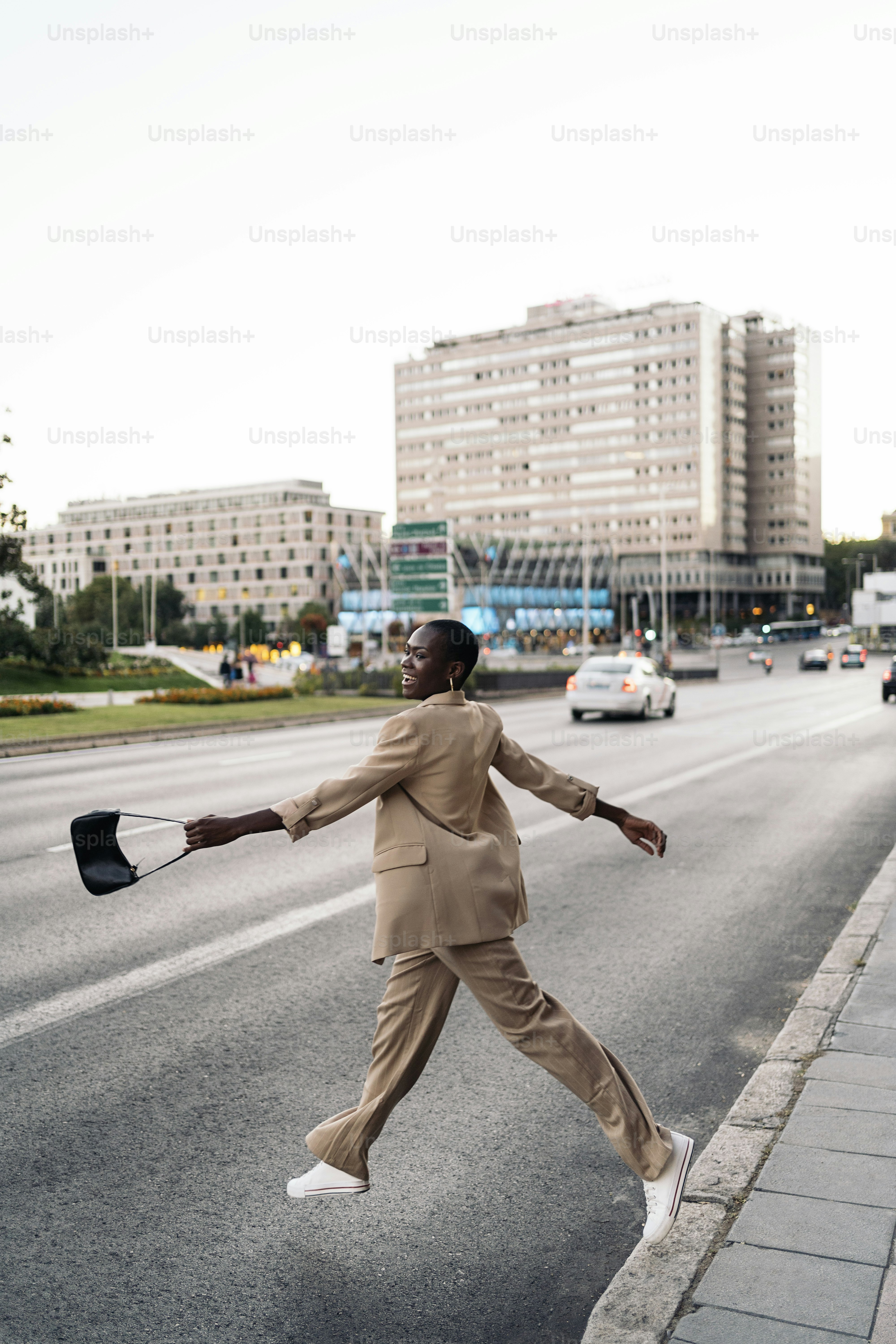 Elegant young adult woman walking with long steps to cross the street ...