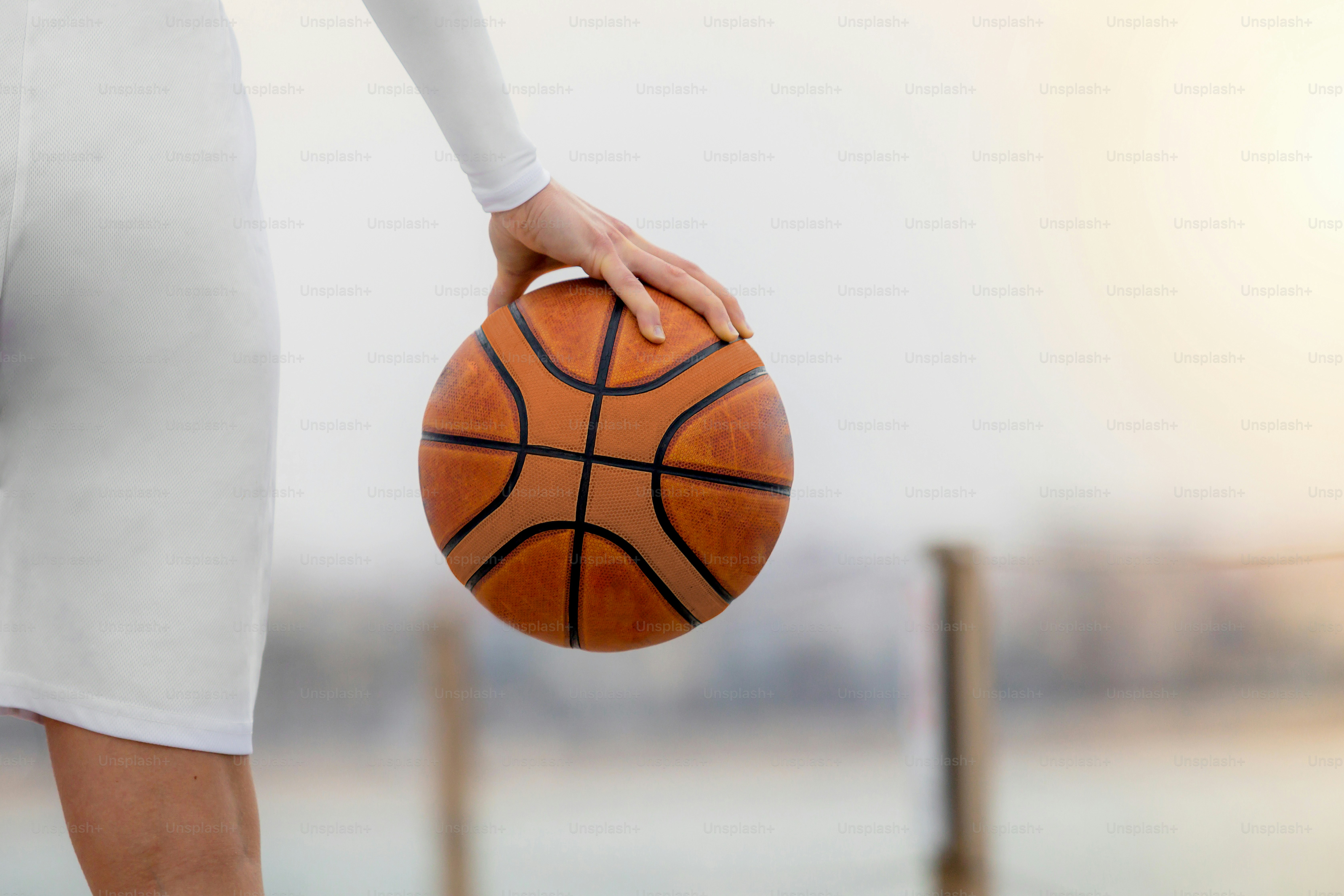 Close-up of a hand holding a basketball with the city in the background ...