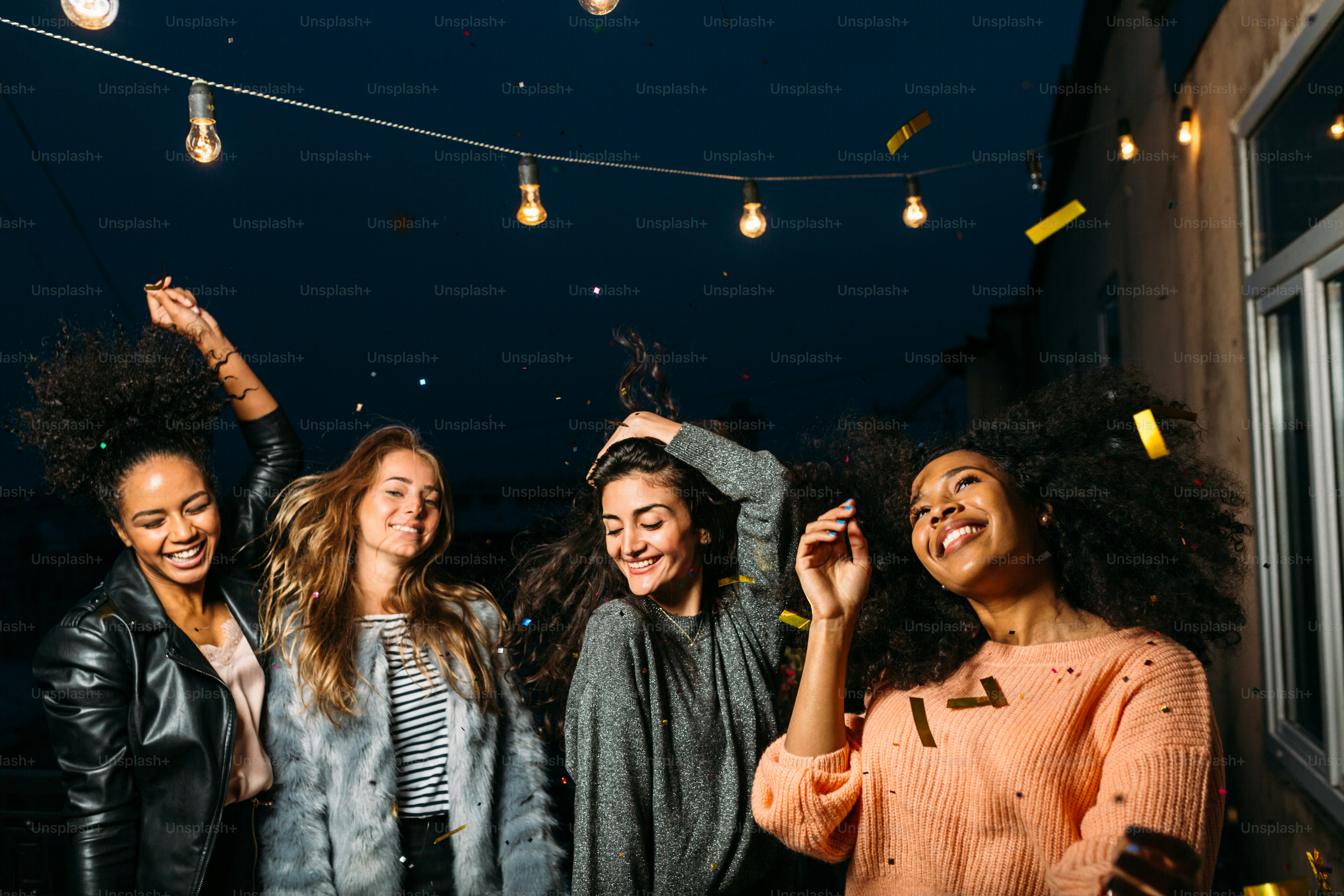 Four beautiful women dancing on a terrace at night photo – Hand raised ...