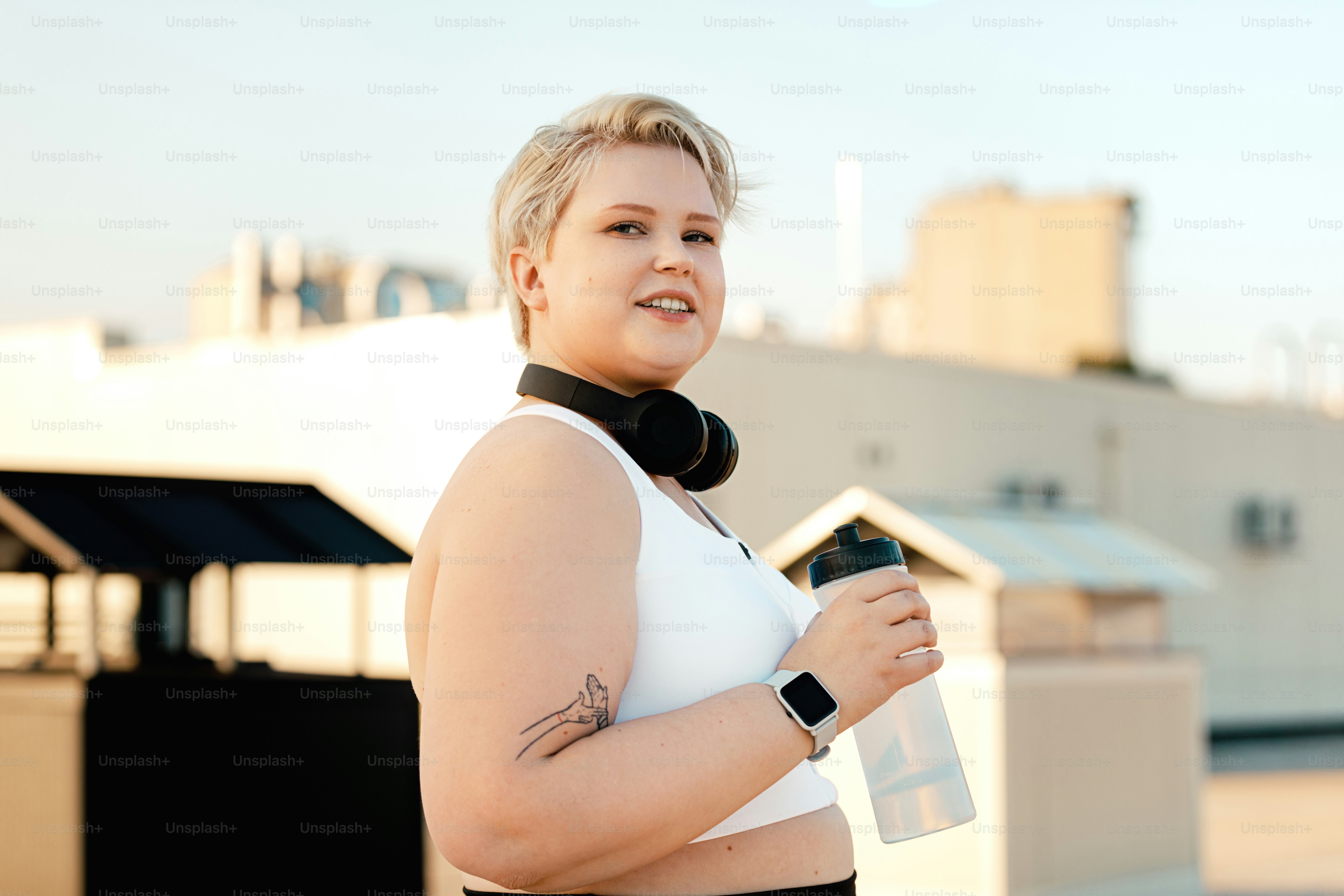 Portrait of a young curvy woman holding a bottle taking a break during ...