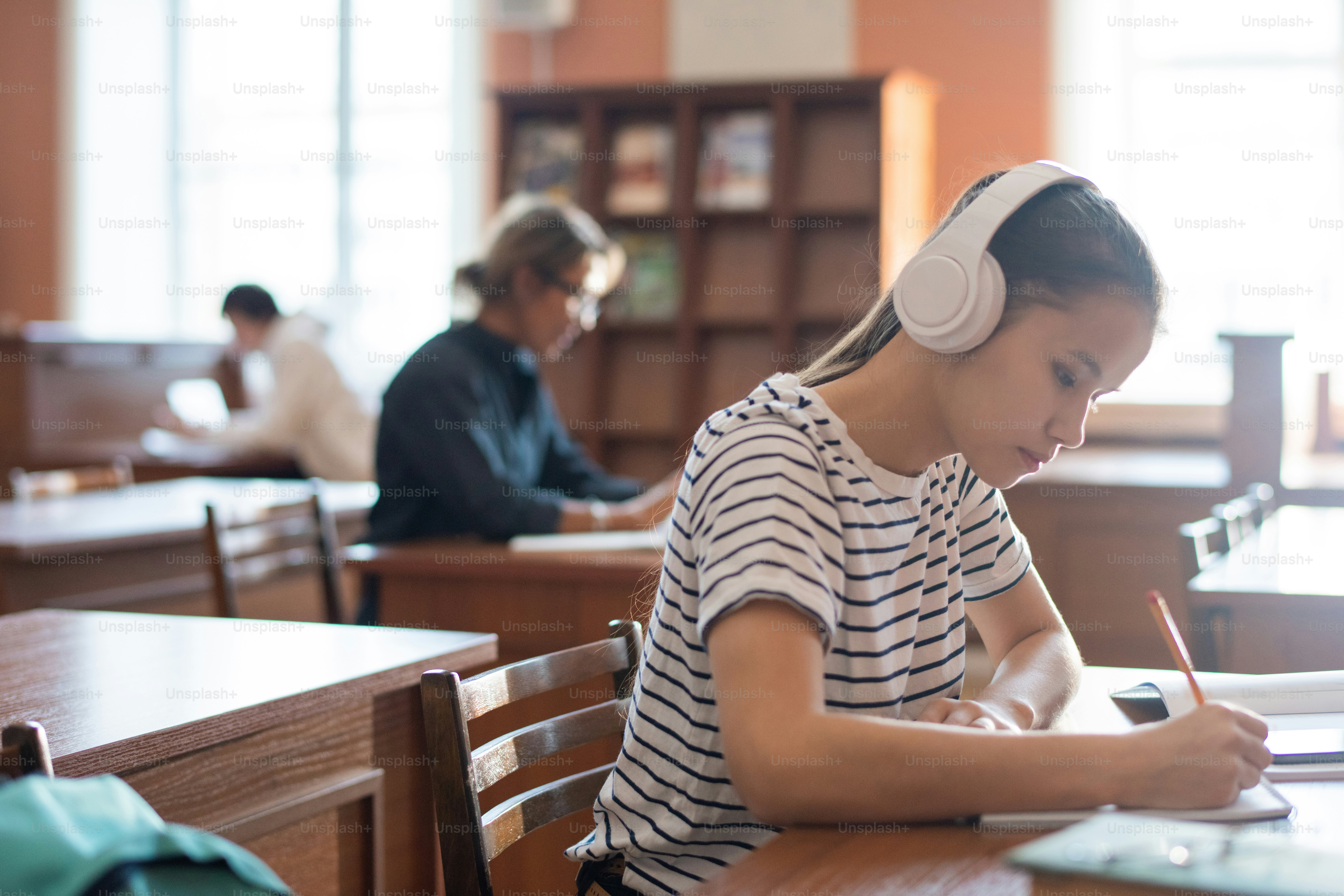 Serious student with headphones concentrating on making plan of report ...