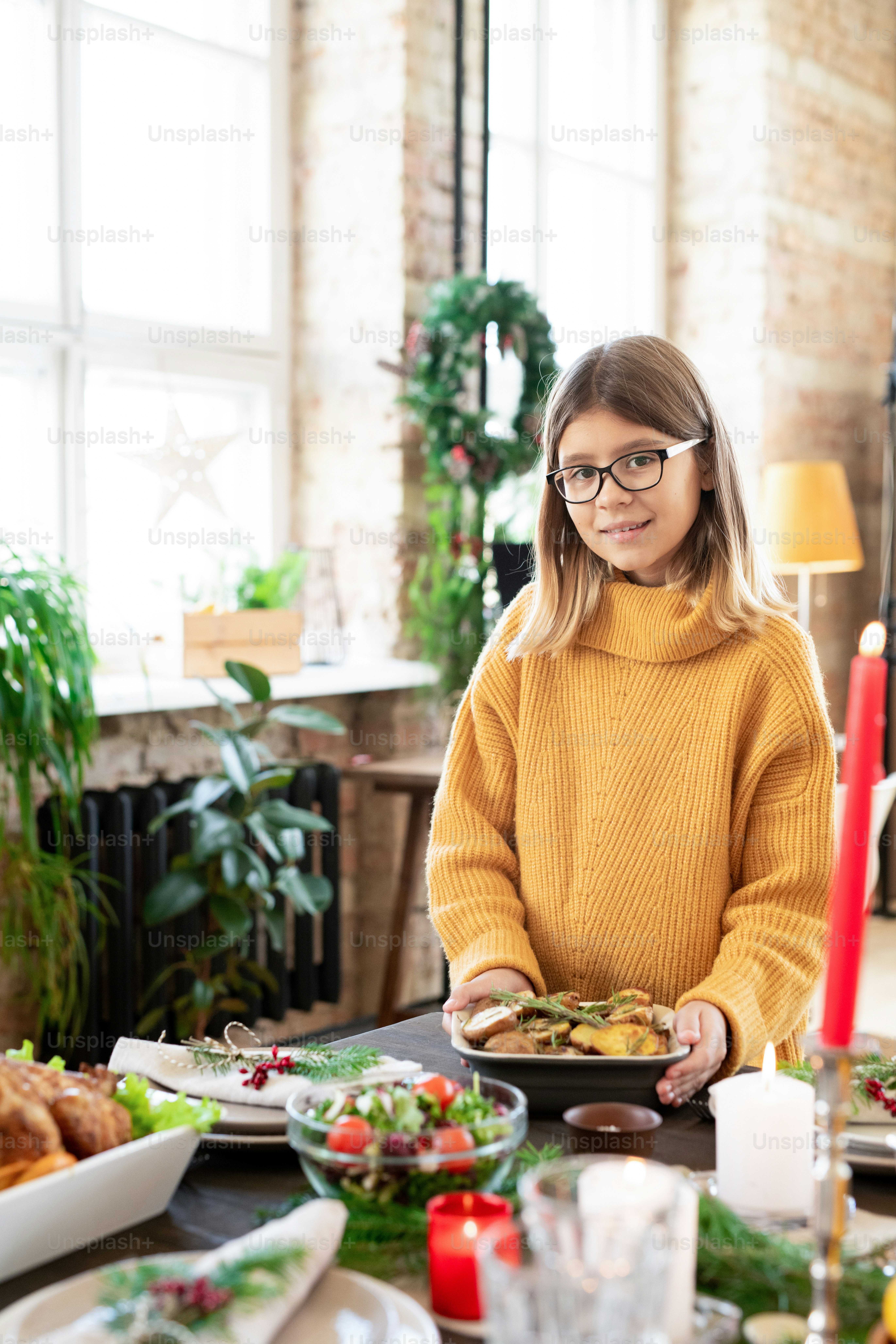 Happy blond girl in eyeglasses and yellow sweater holding bowl with ...