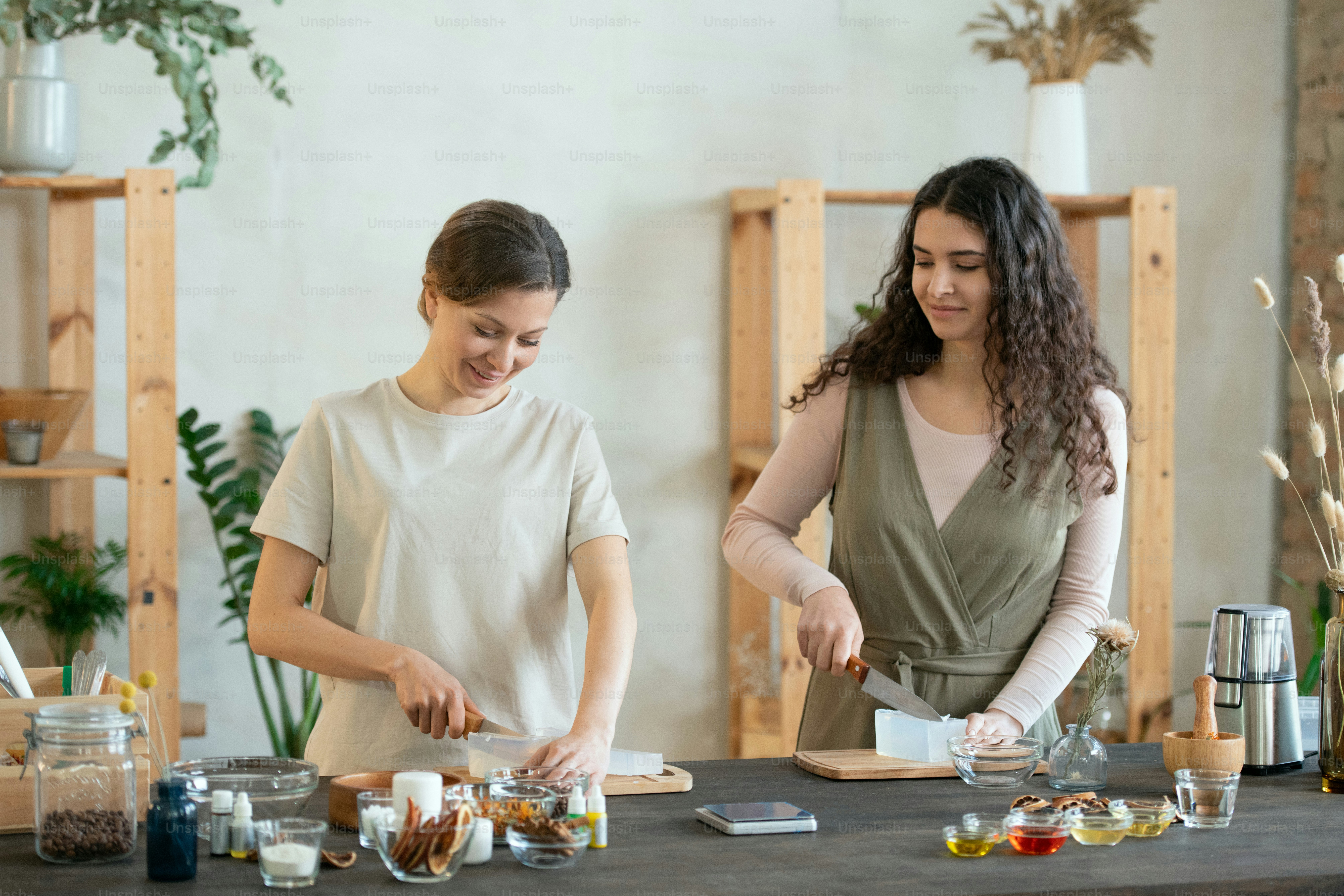 Young female pouring liquid green colorant into bowl with melted soap ...