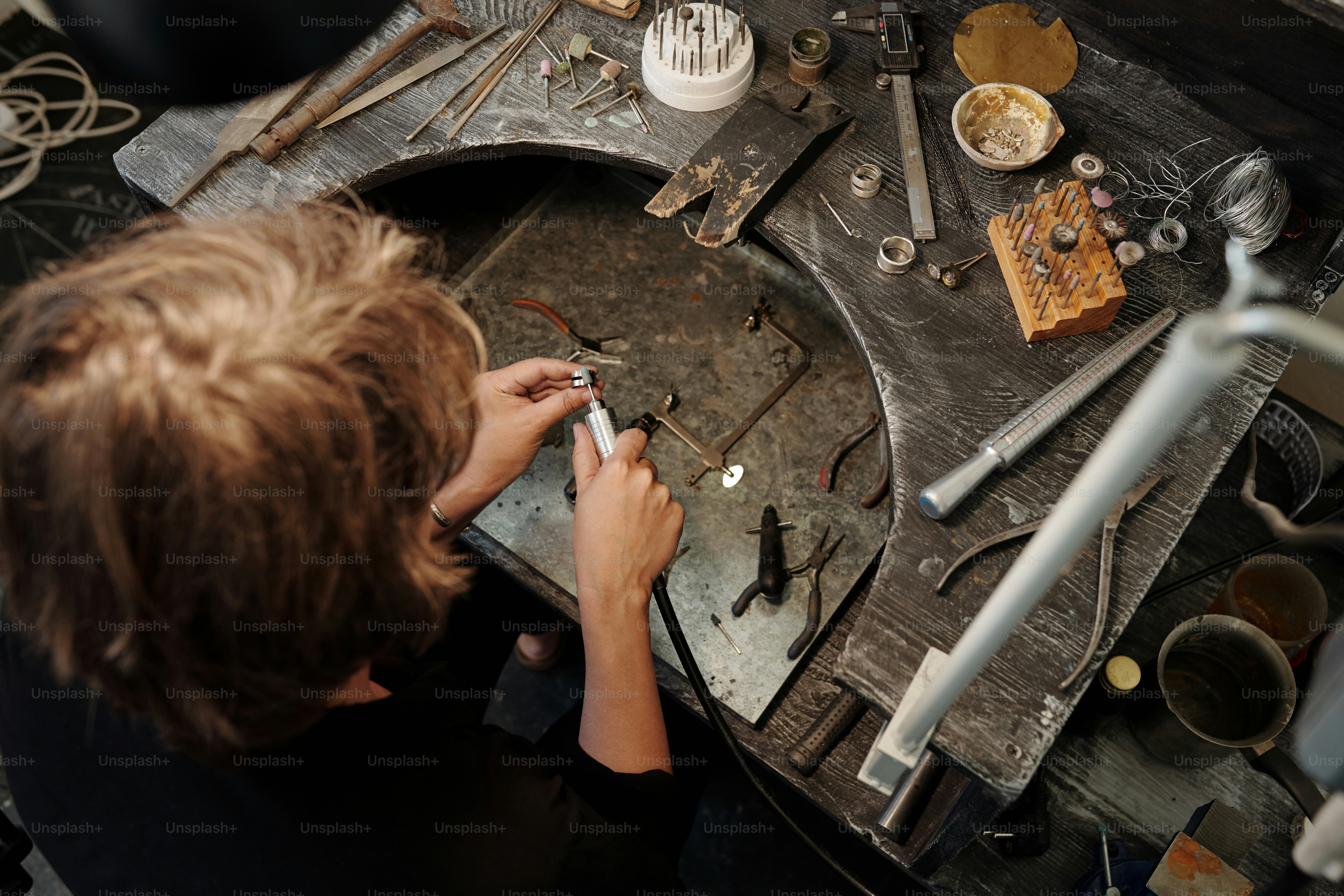 High angle view of jeweler using abrasive tool while polishing silver ...