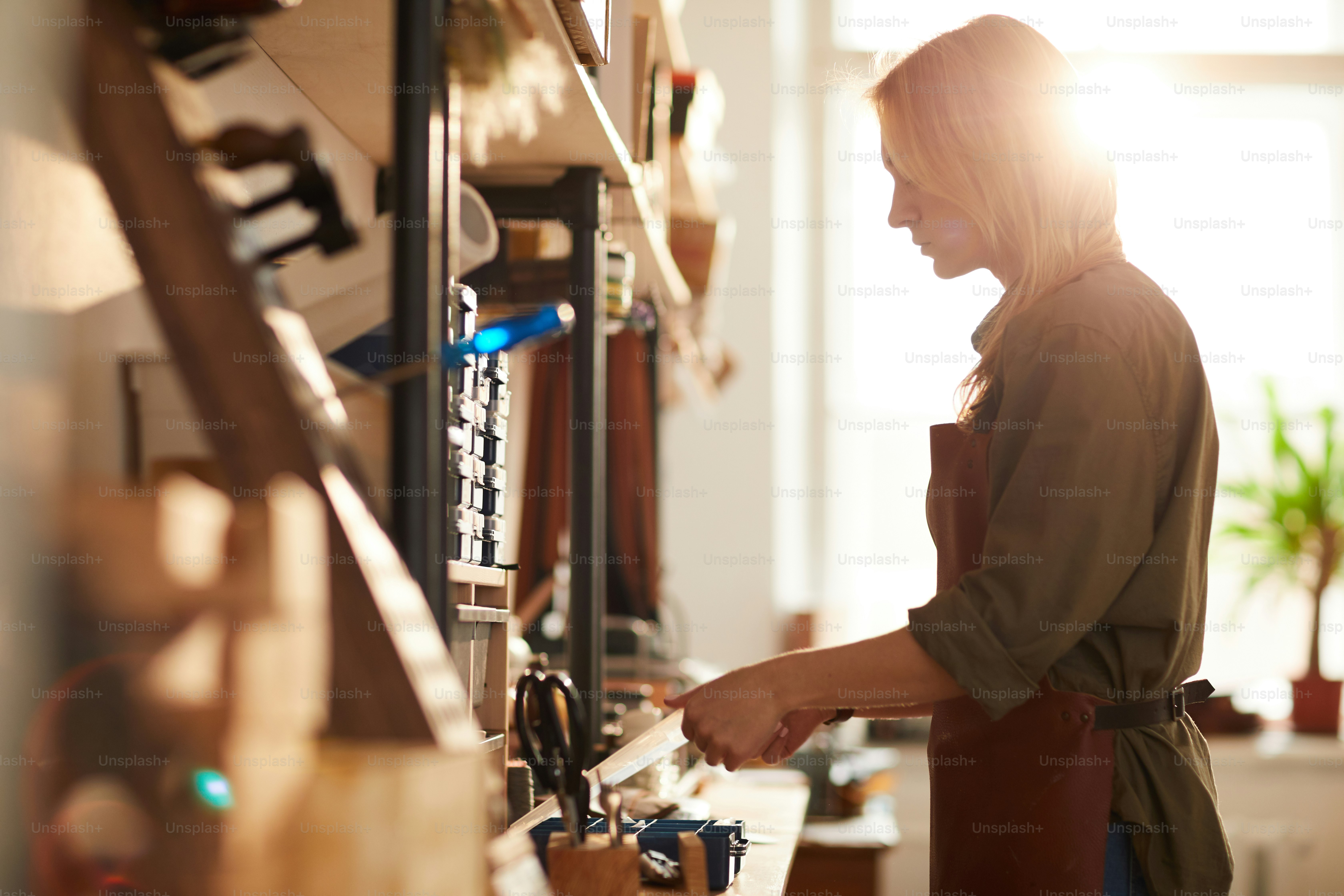 Side view portrait of female tanner working with leather in workshop ...