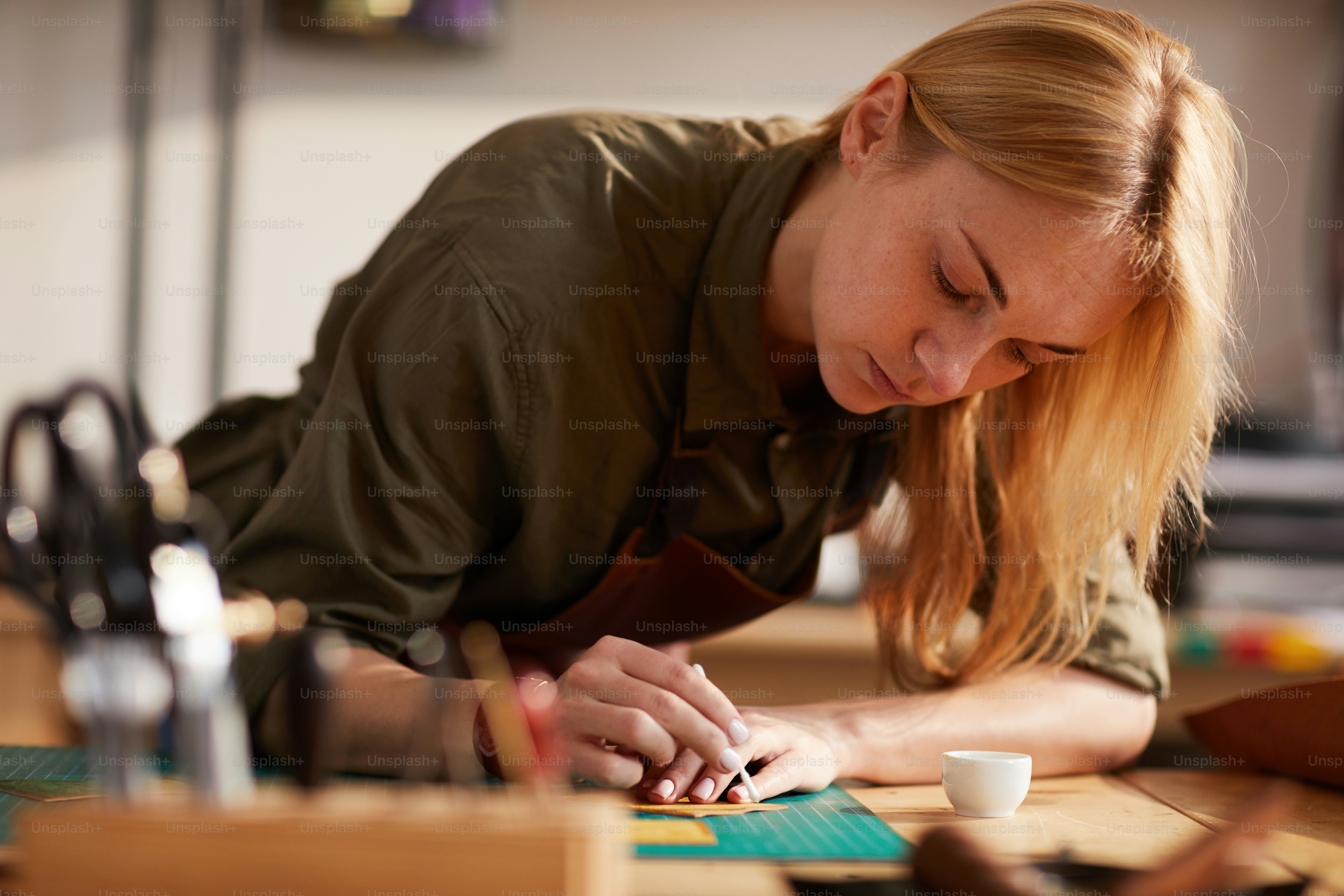 Warm toned portrait of young woman tracing leather patterns while ...
