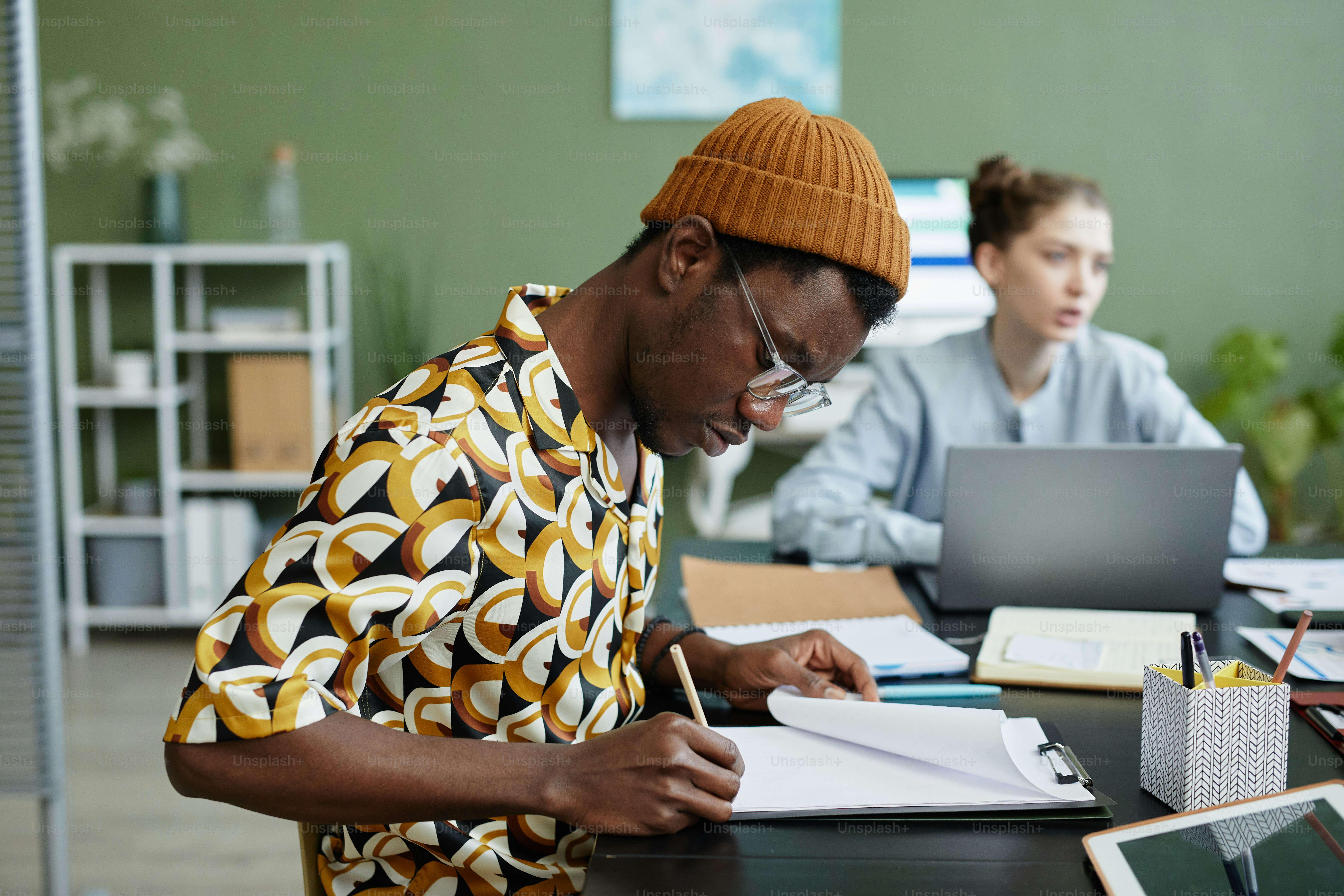 Side view at black young man taking notes in business meeting with ...