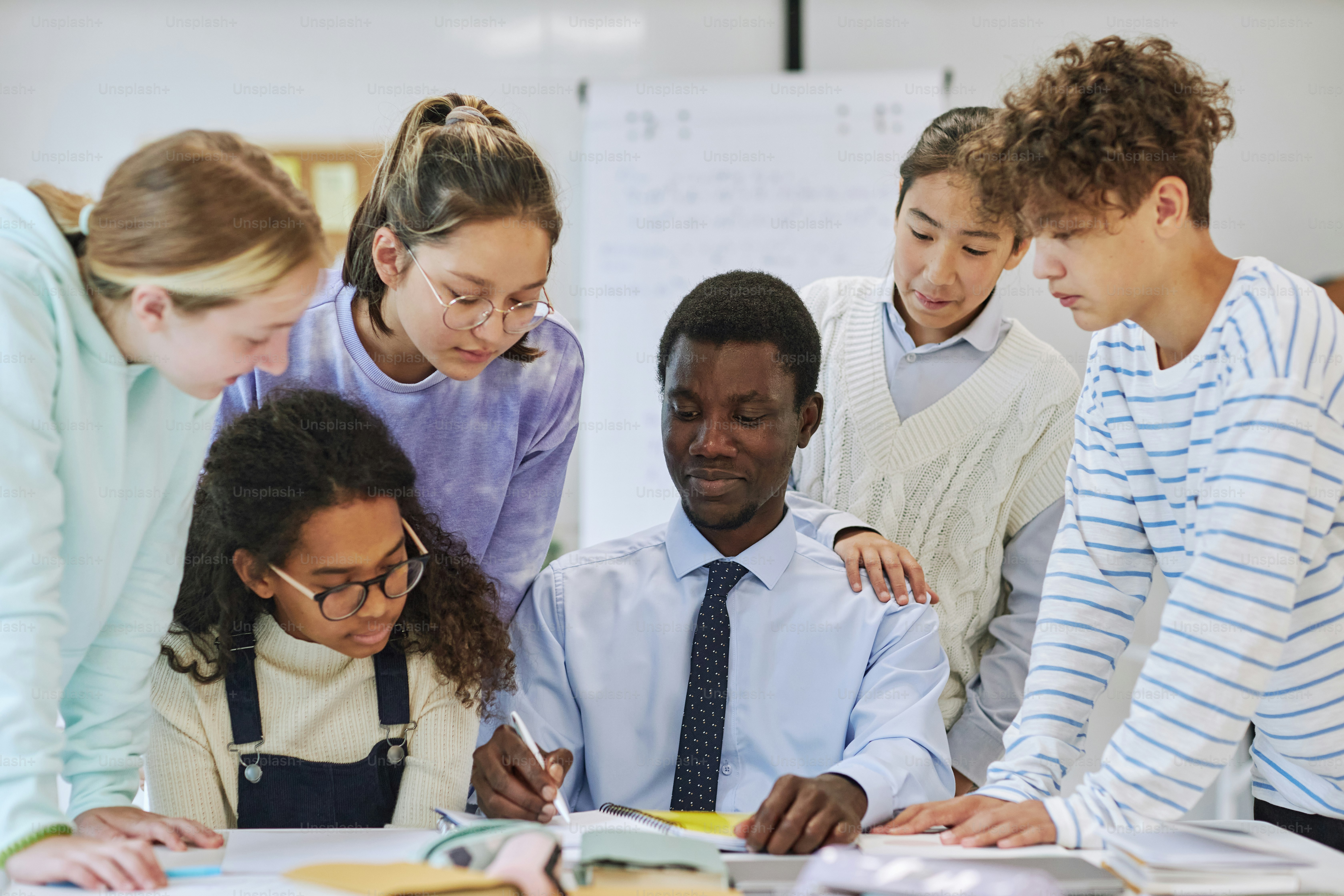 Portrait of young black teacher smiling with diverse group of children ...