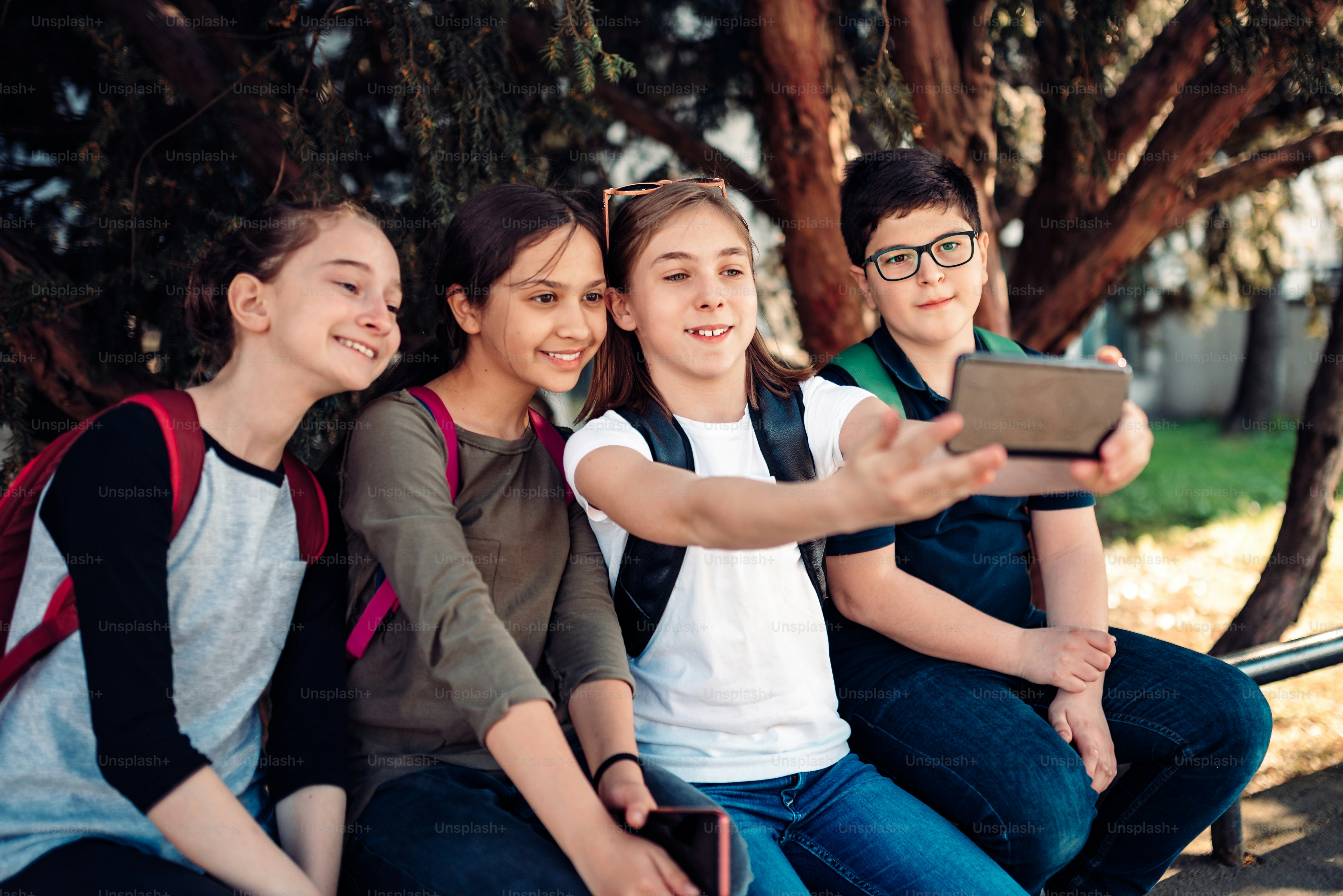 Classmates hang out in the shade of the tree after school and taking ...