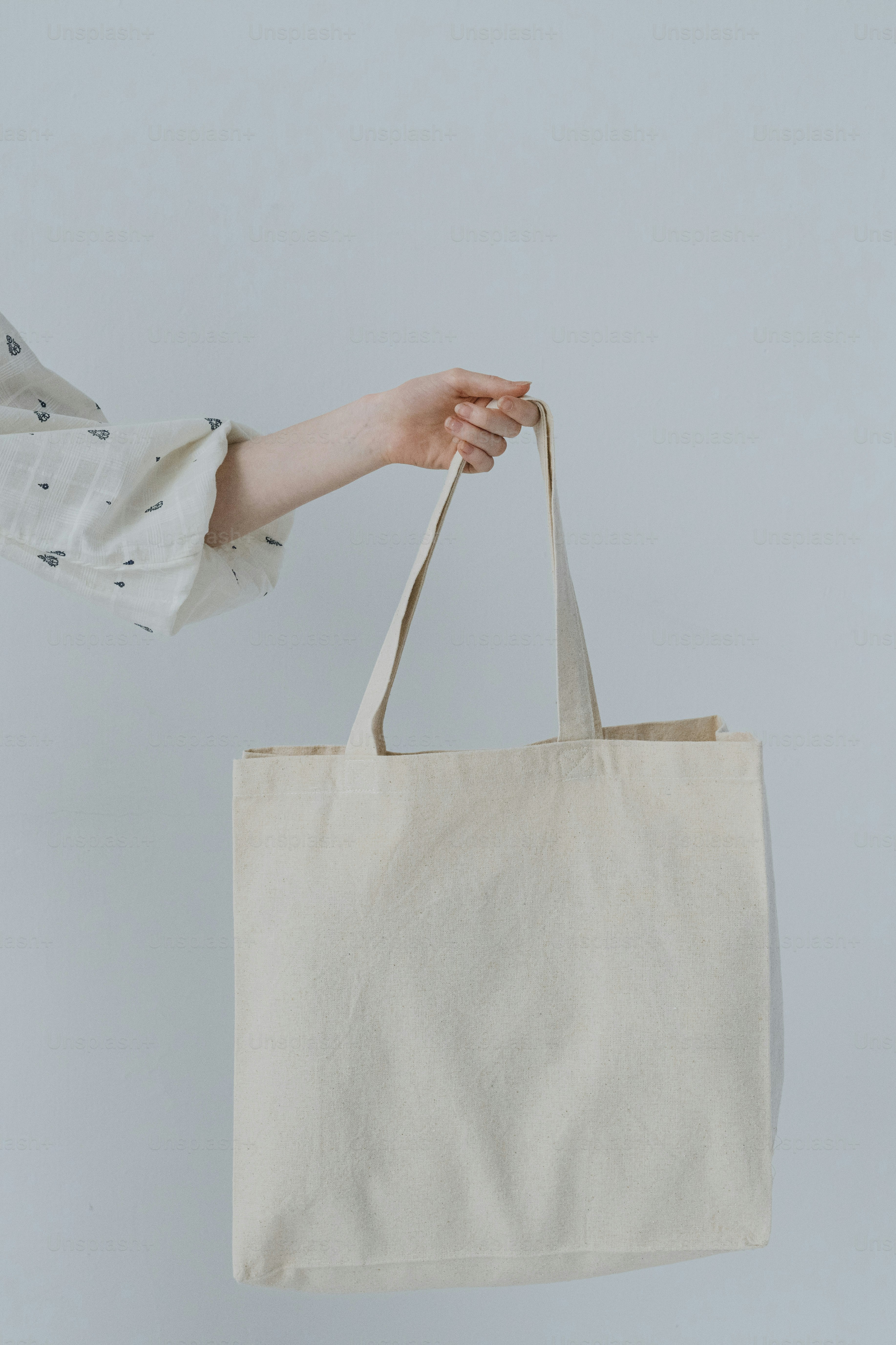 A person holding a white bag in their hand photo – Tote bag Image on ...