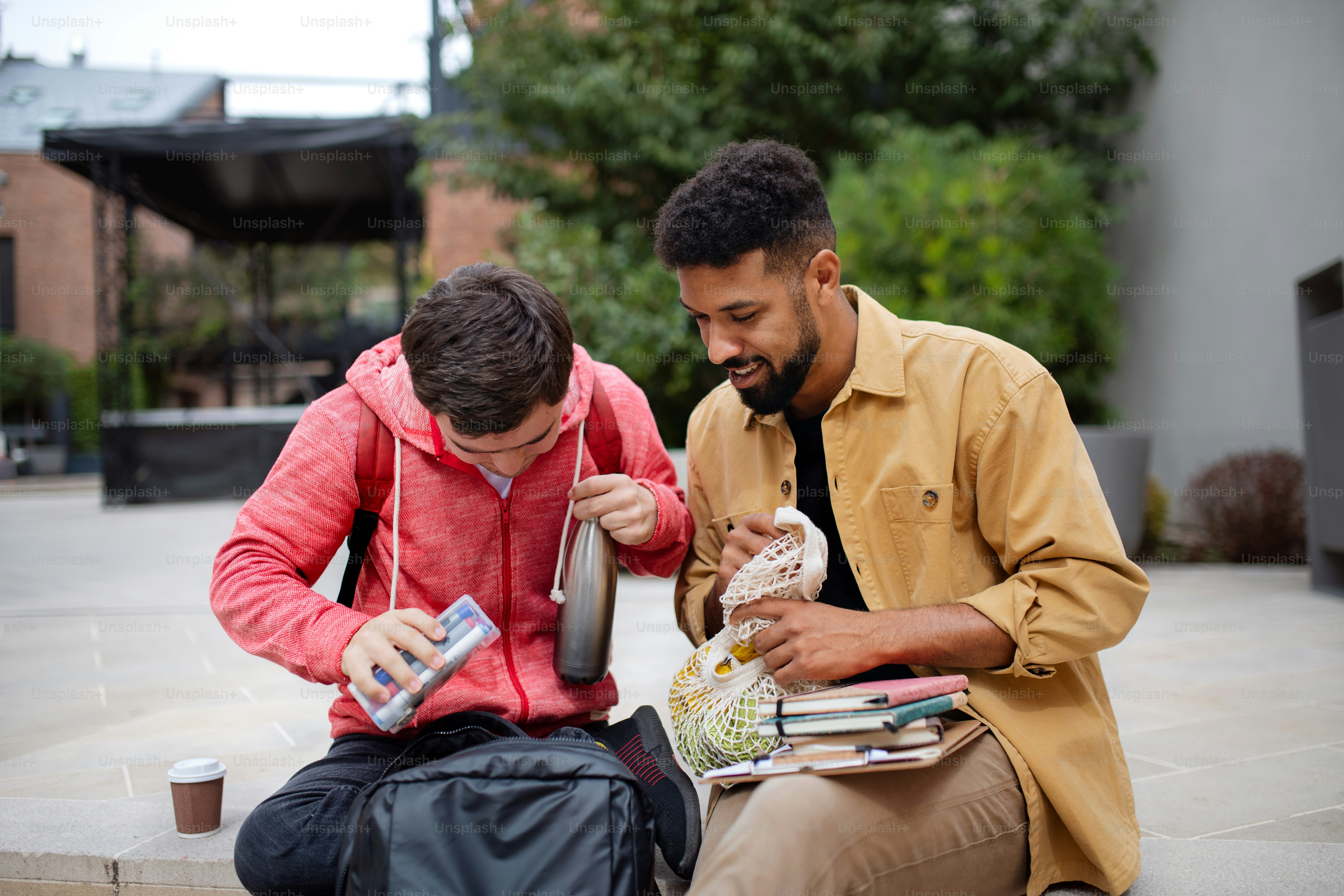 A young man student with Down syndrome and his mentoring friend sitting ...