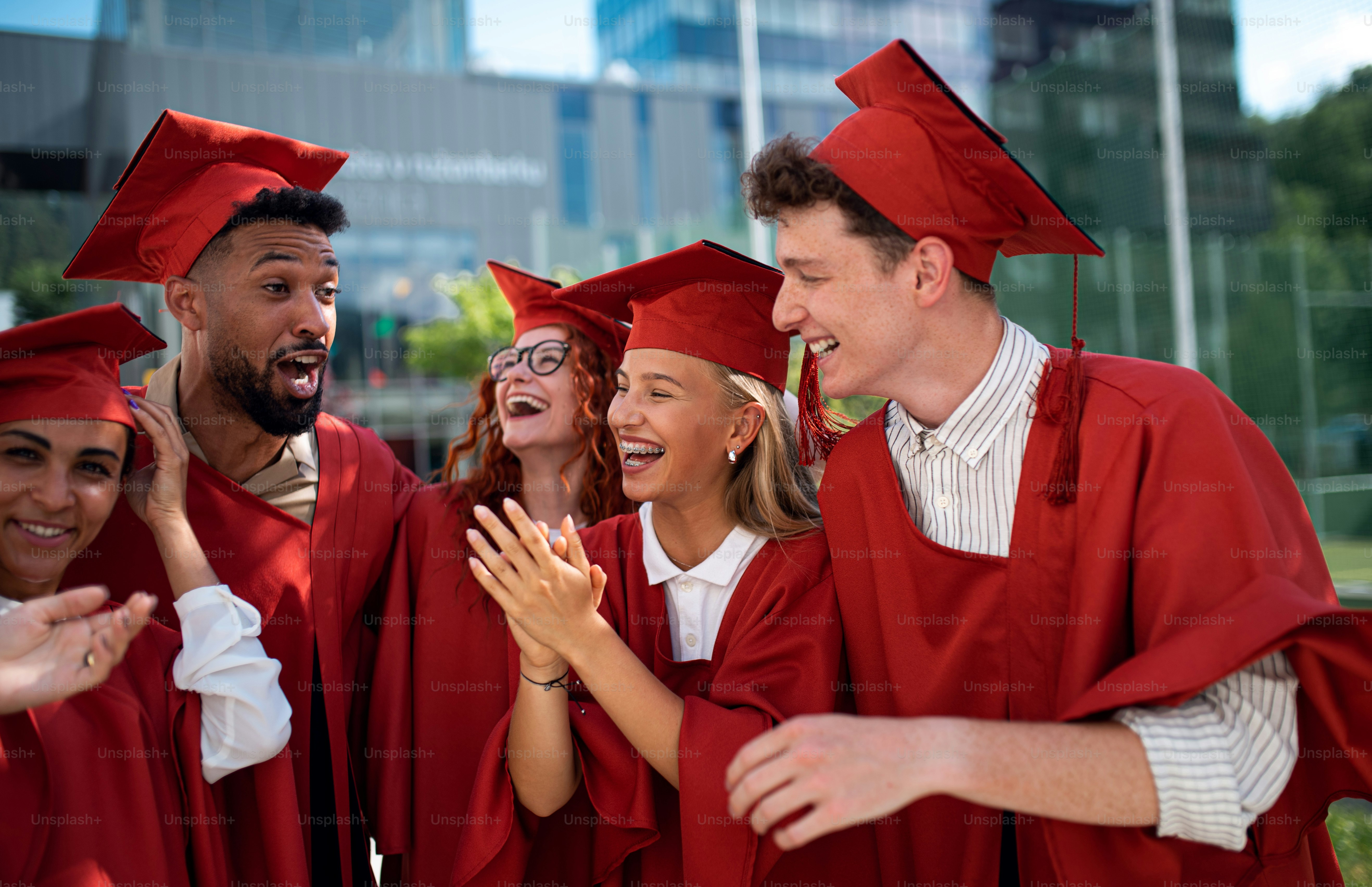 A group of cheerful university students celebrating outdoors ...