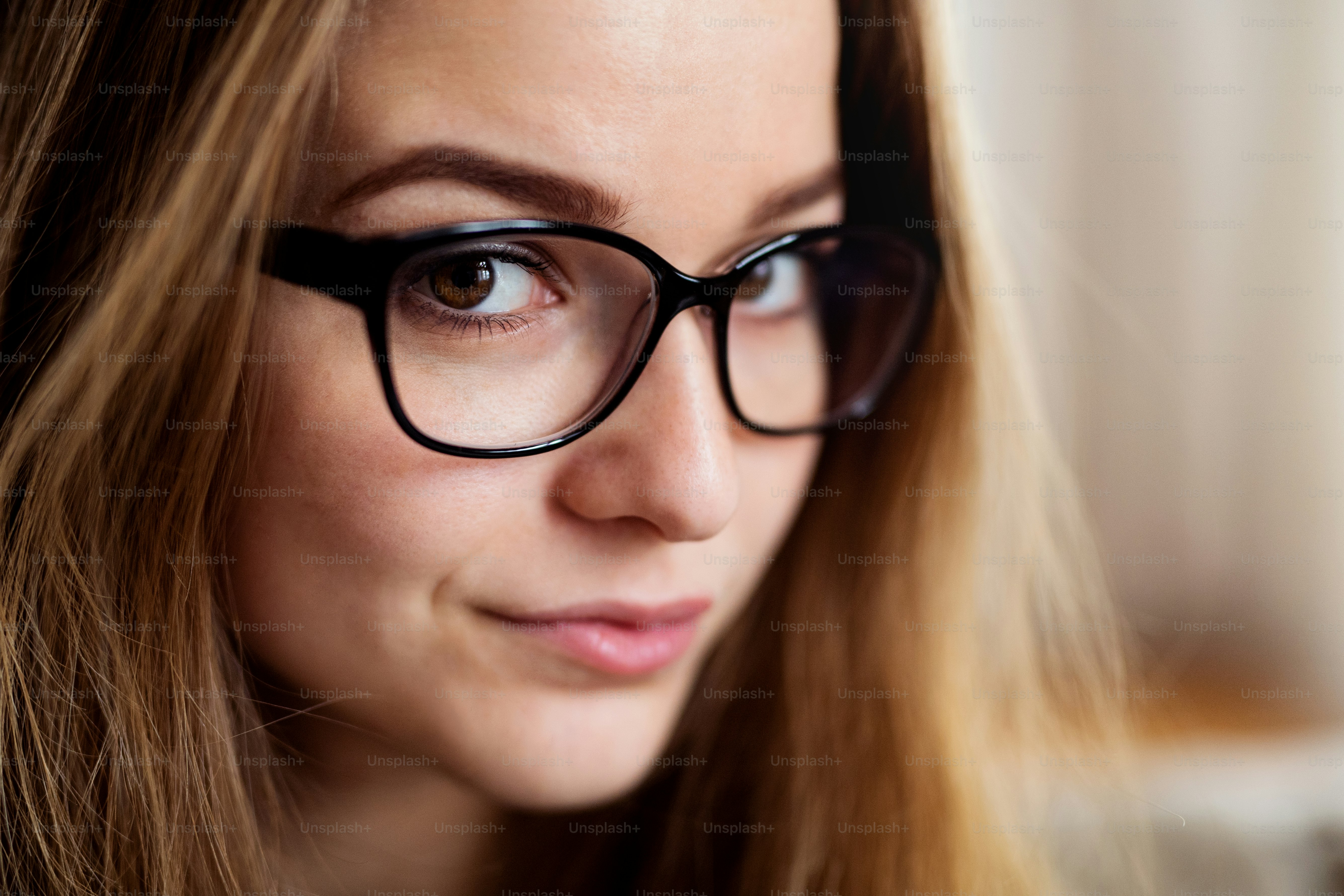 A close-up portrait of happy young female student standing indoors ...