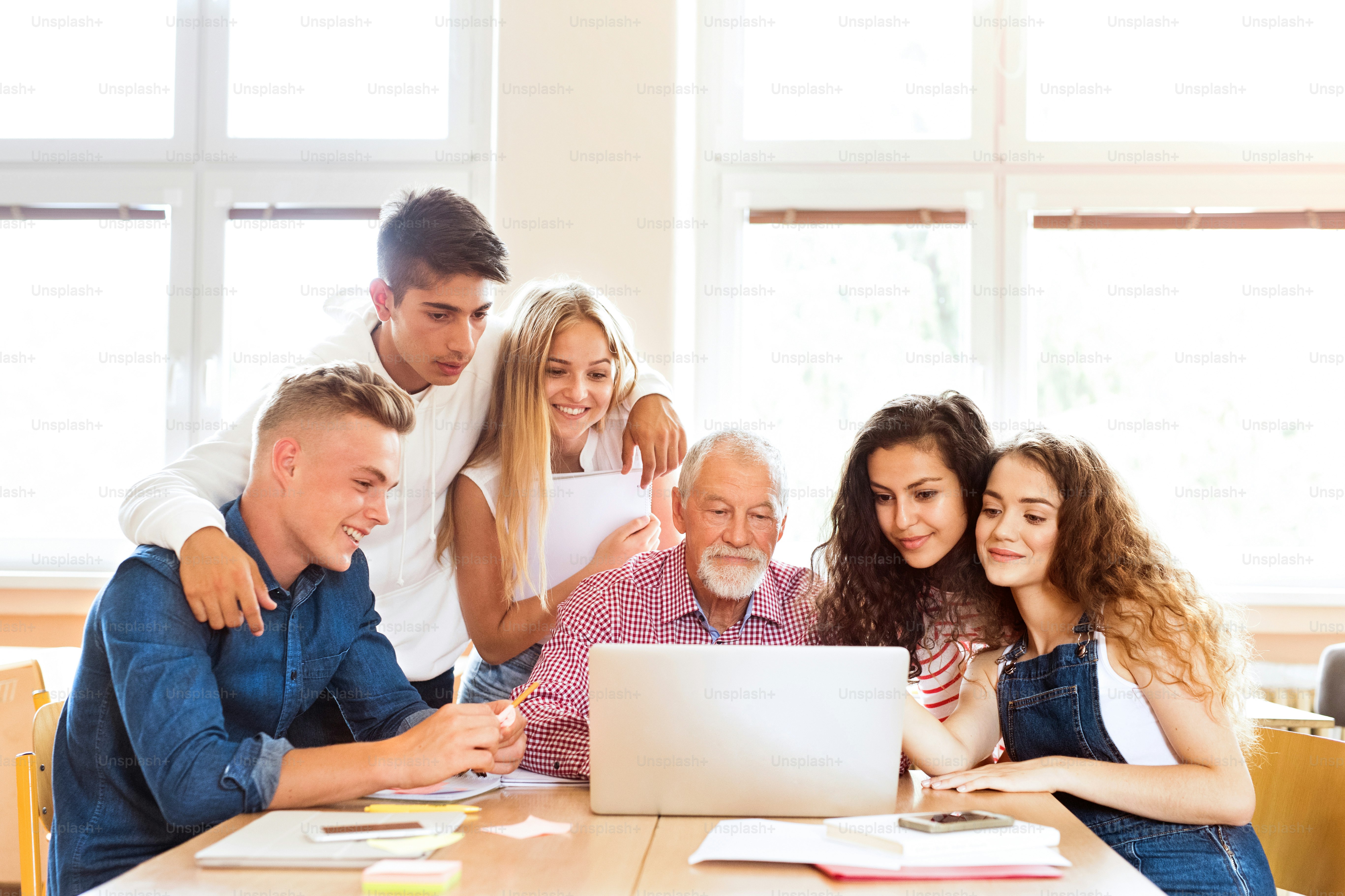 Group of high school student and their teacher with laptop studying ...
