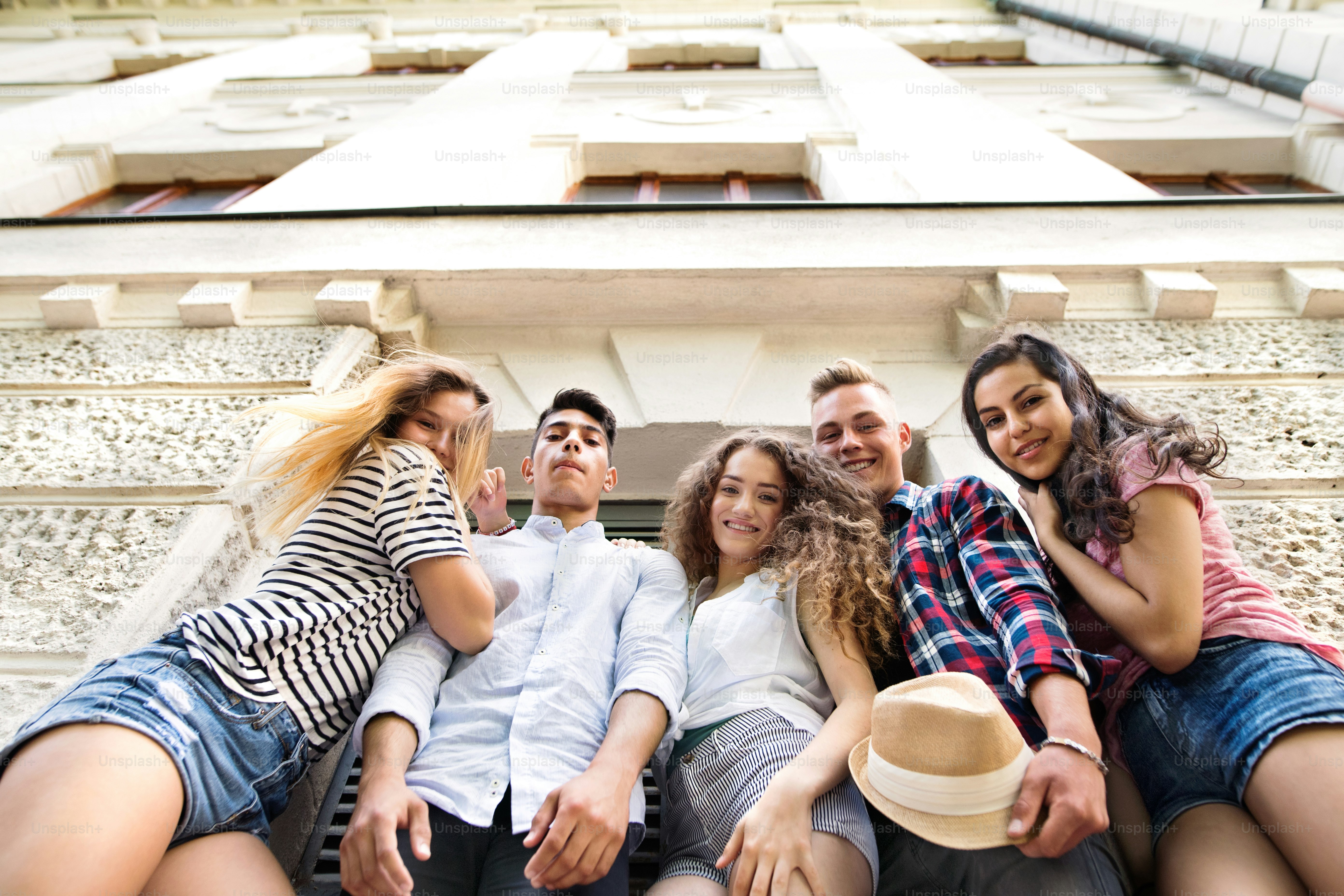 Group of attractive teenage students posing in front of university ...