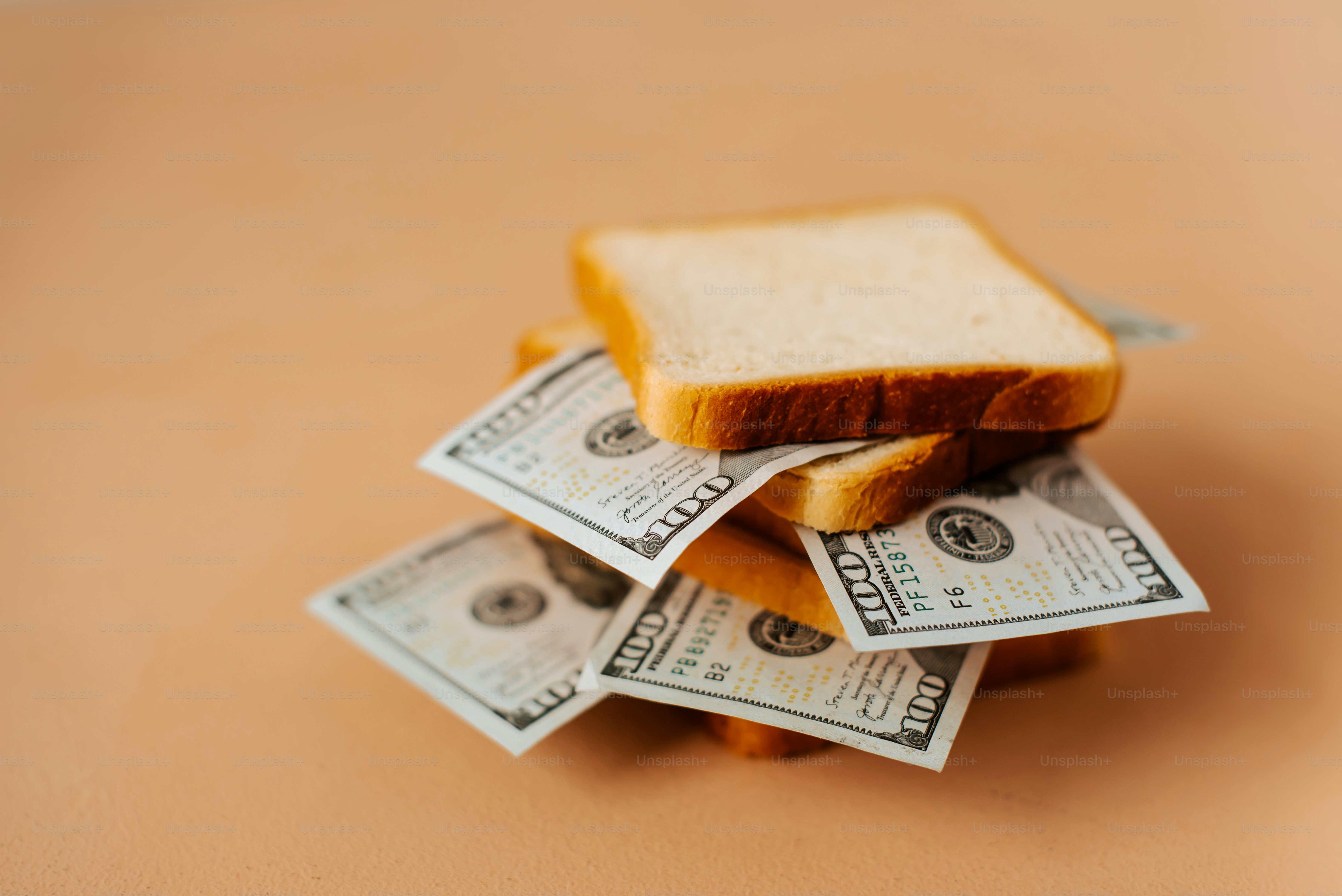 A pile of money sitting on top of a piece of bread photo – Currency ...