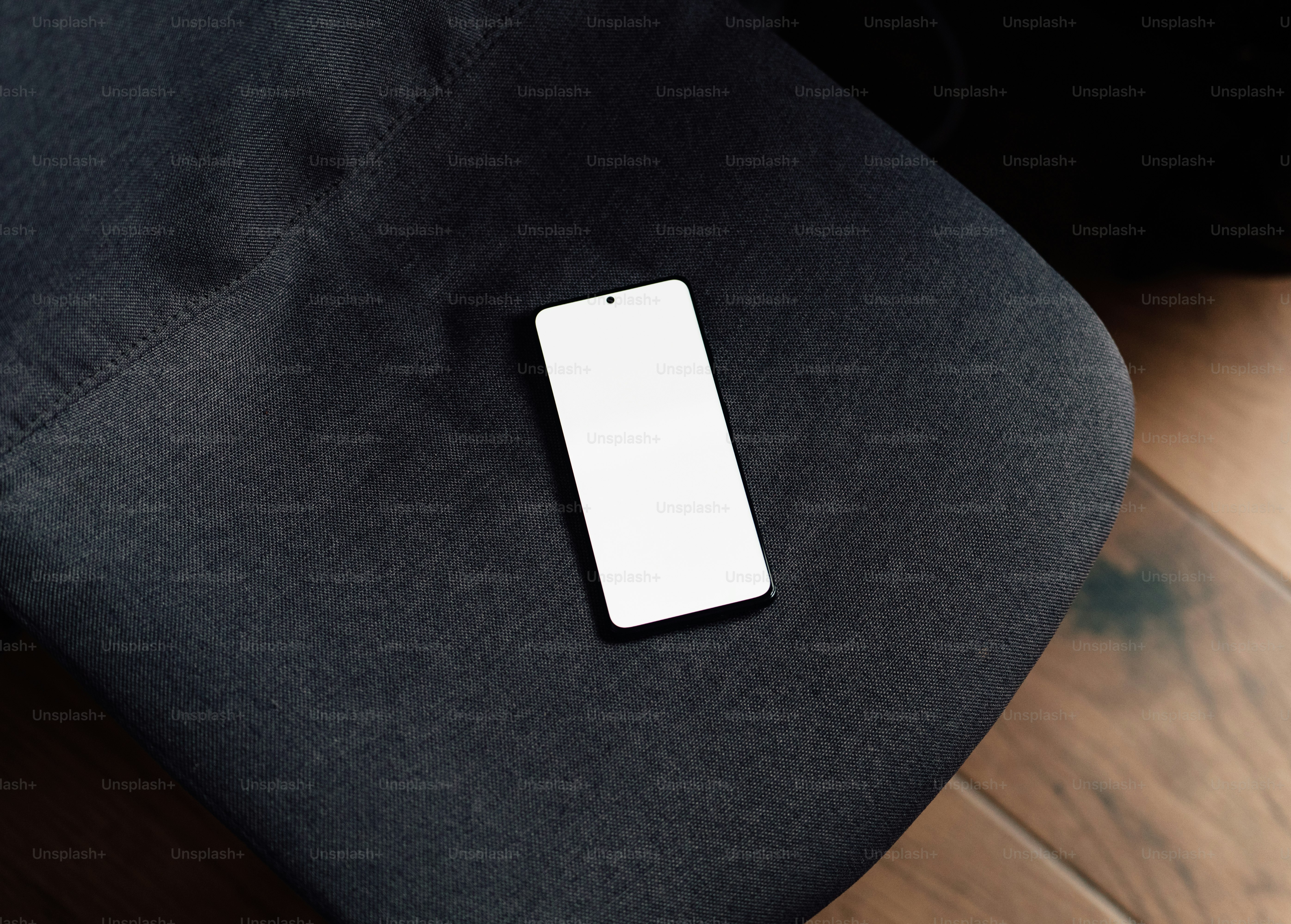 A cell phone sitting on top of a black chair photo – Mockup Image on ...
