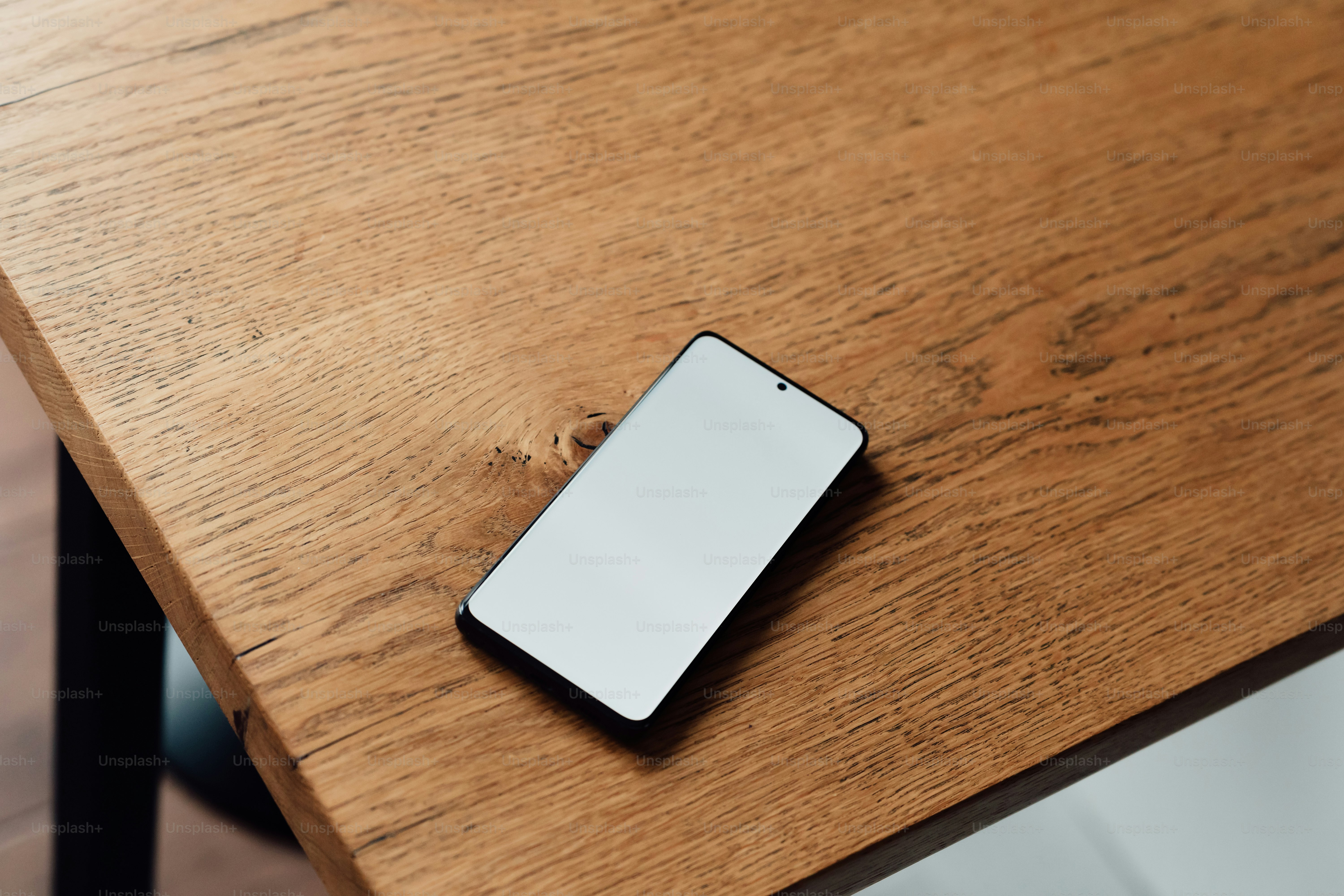 A cell phone sitting on top of a wooden table photo – Mockup Image on ...