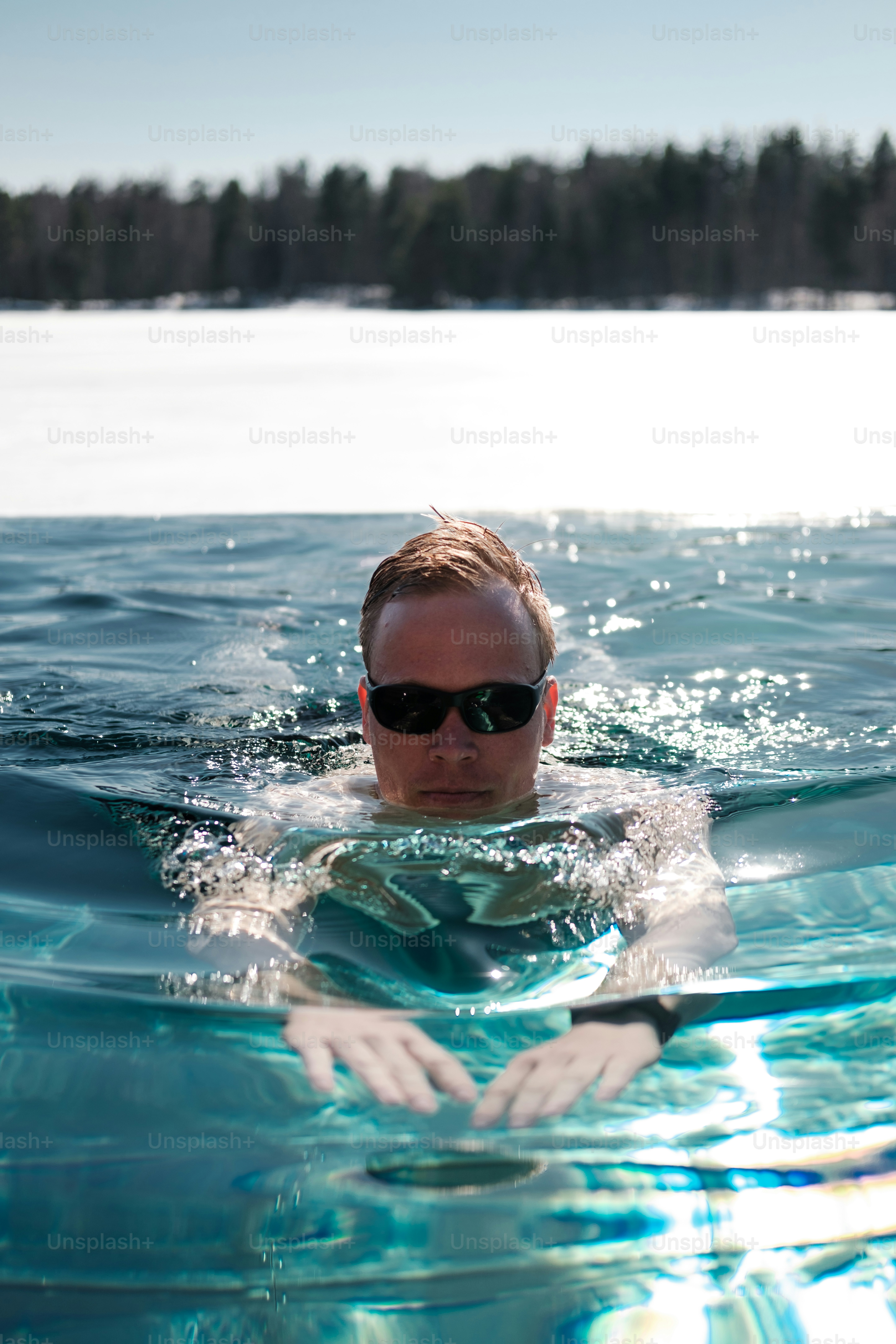 A man swimming in a lake with trees in the background photo – Man Image ...