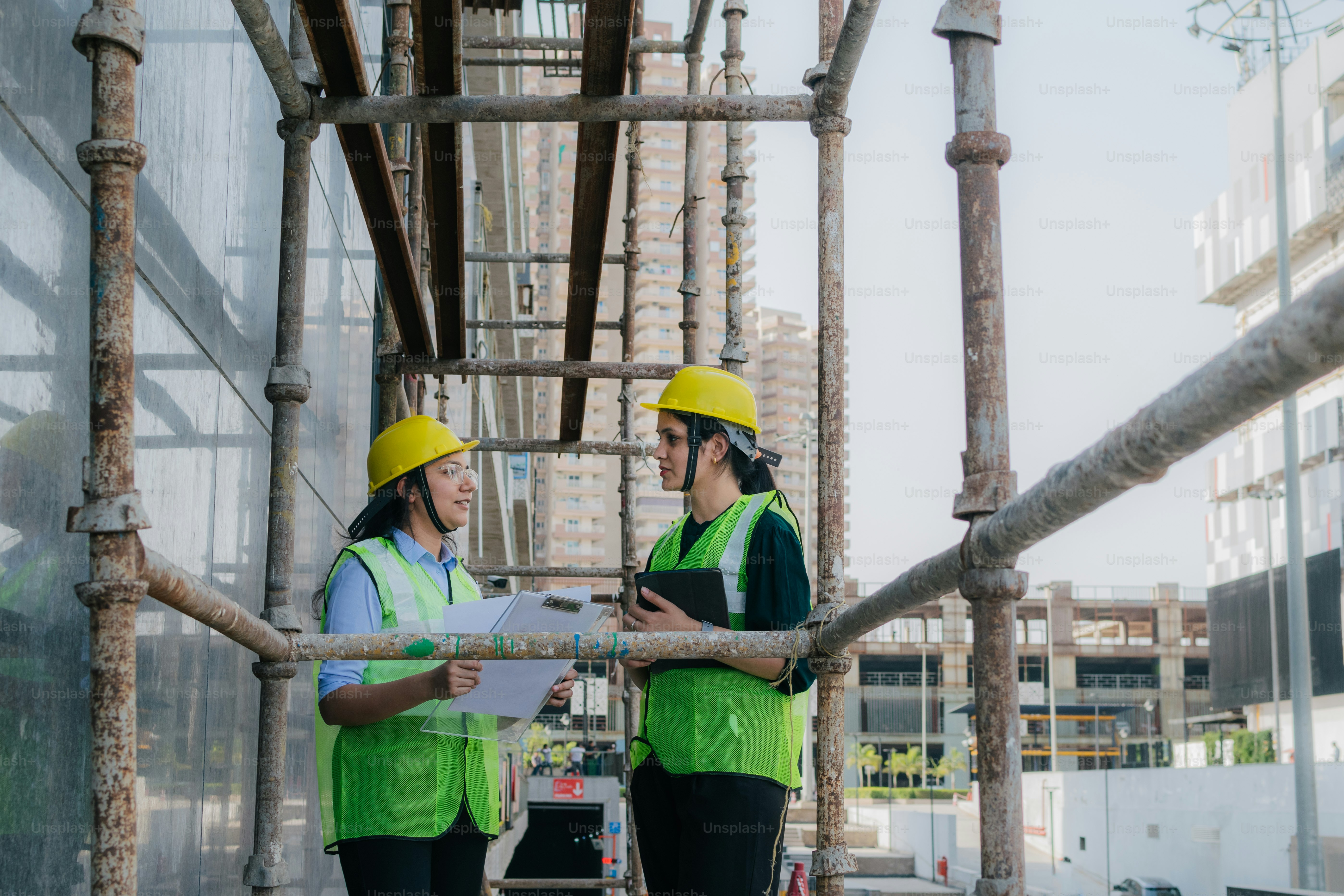 Two construction workers standing in front of a building under ...