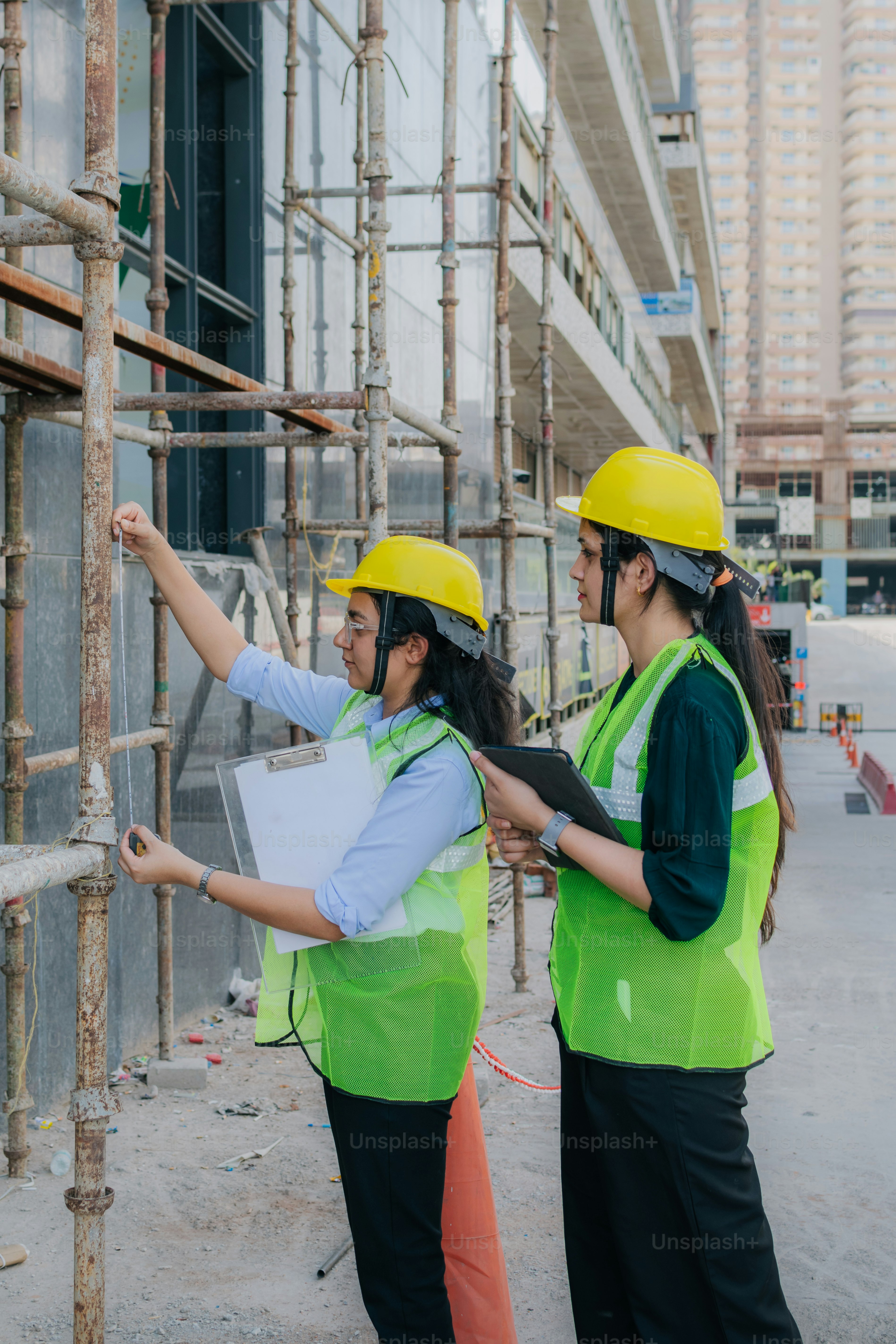 A couple of women standing next to each other photo – Construction ...