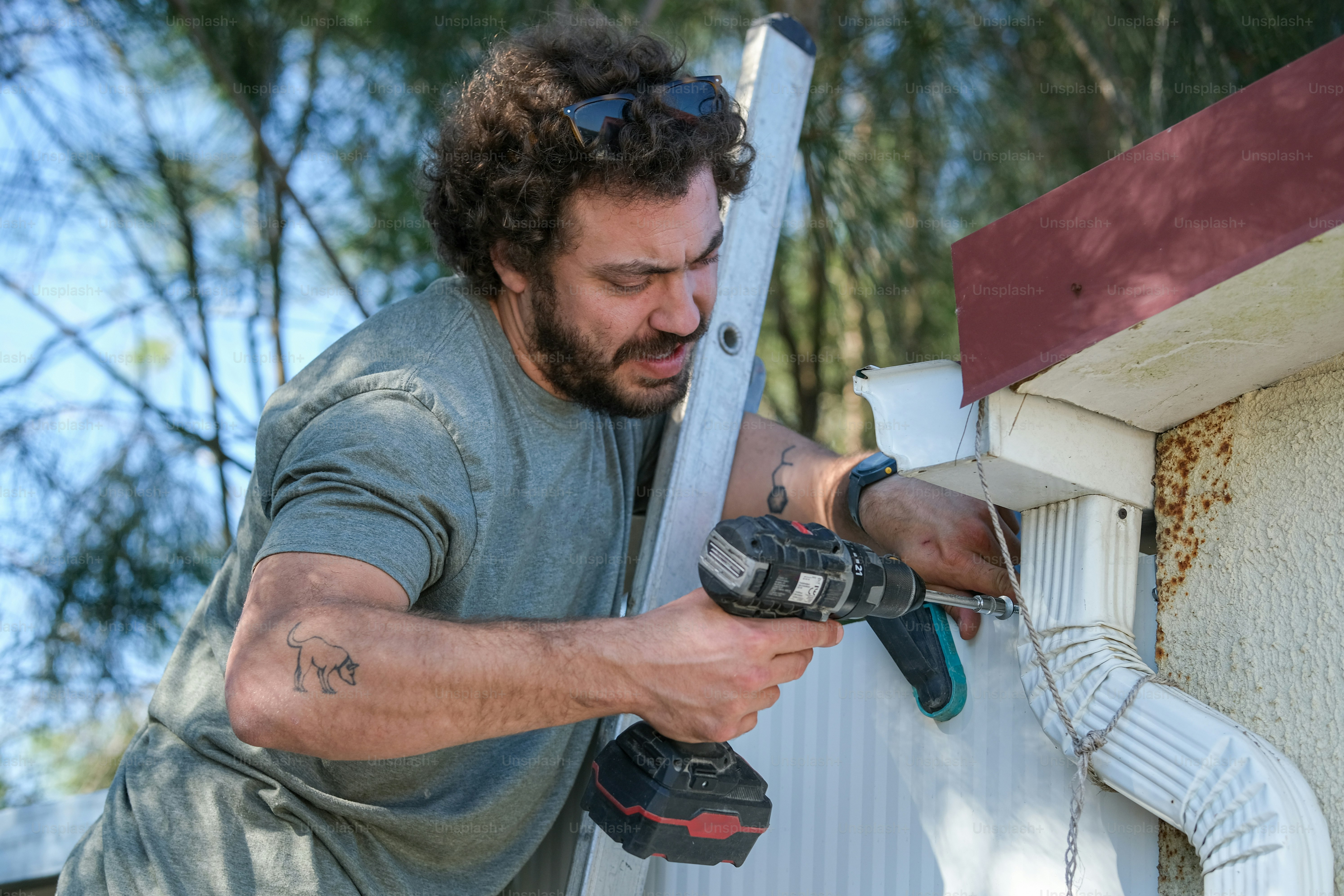 A man using a drill to fix a gutter gutter photo – Construction Image ...
