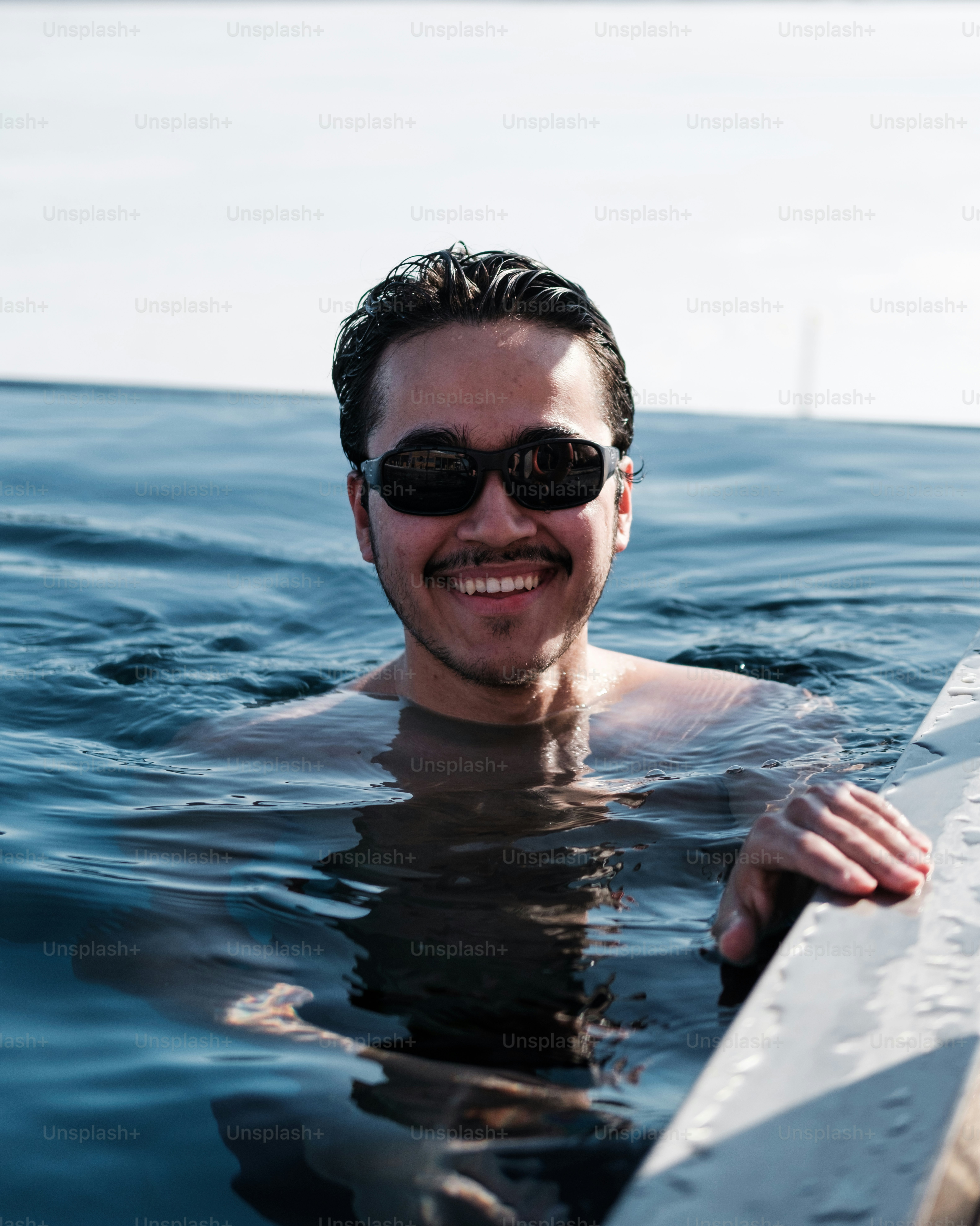 A man swimming in the ocean with his head above the water photo ...