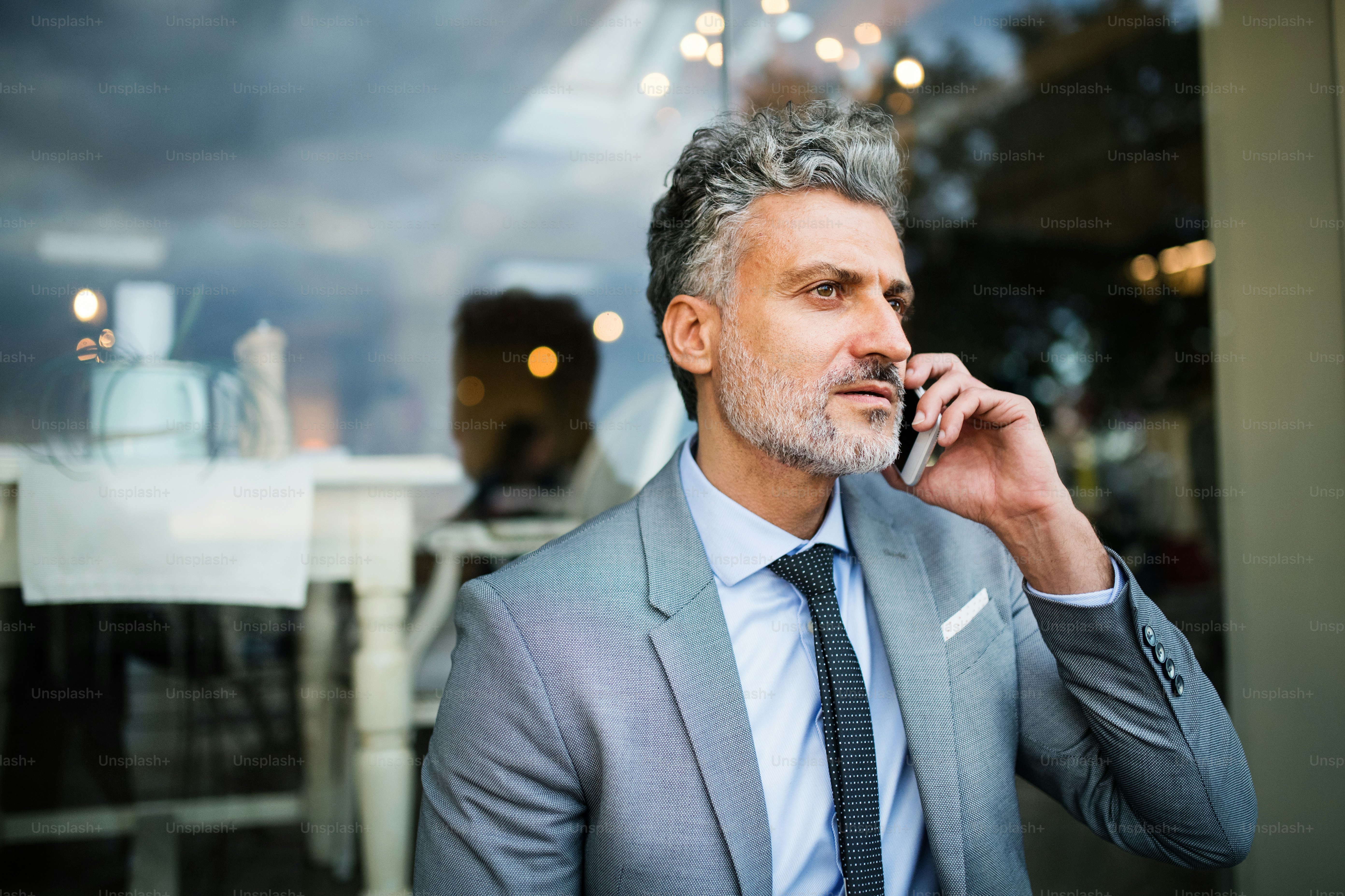 Mature businessman standing at the big windows in a hotel. Man looking ...