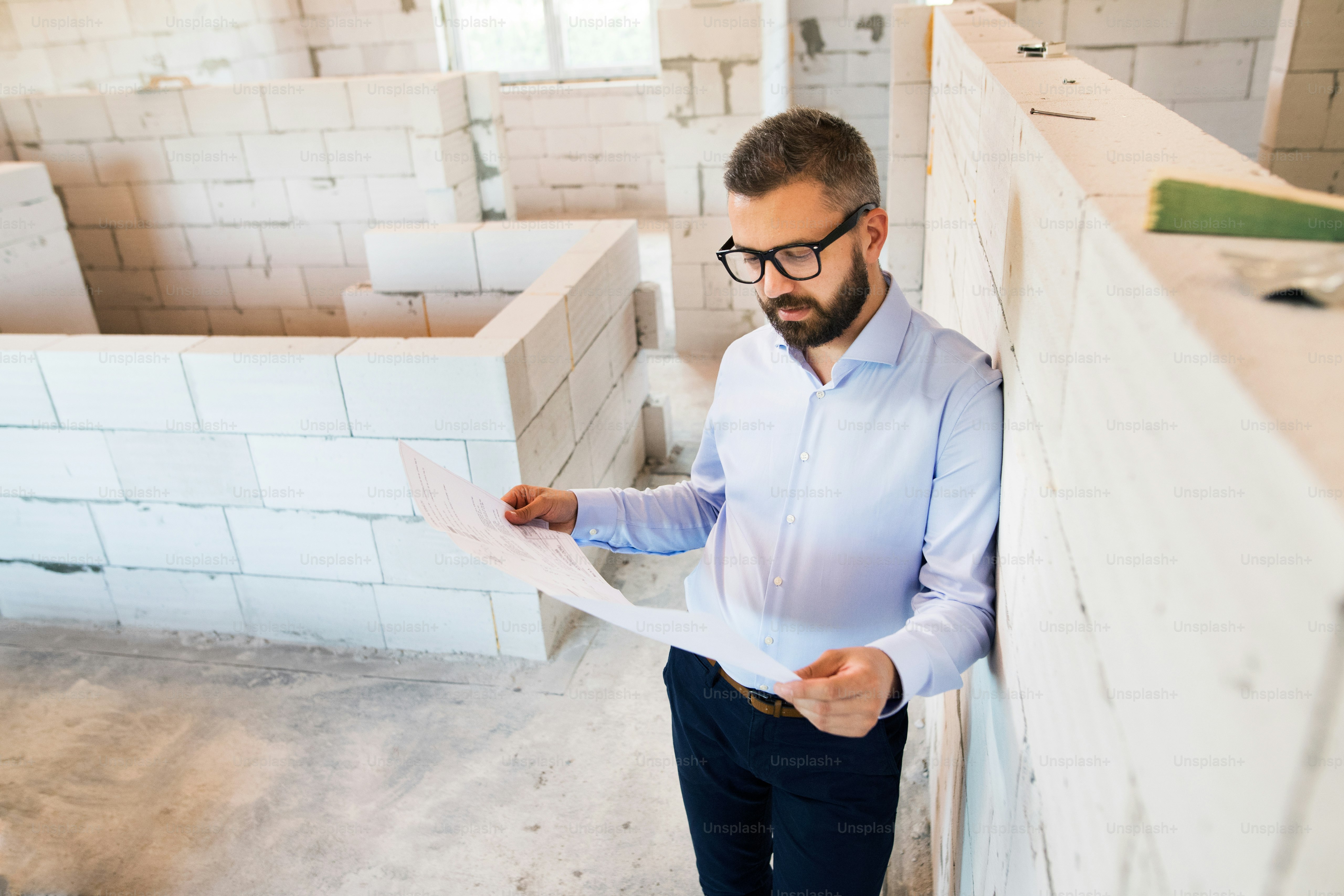 Young hipster architect or home owner at the construction site looking ...