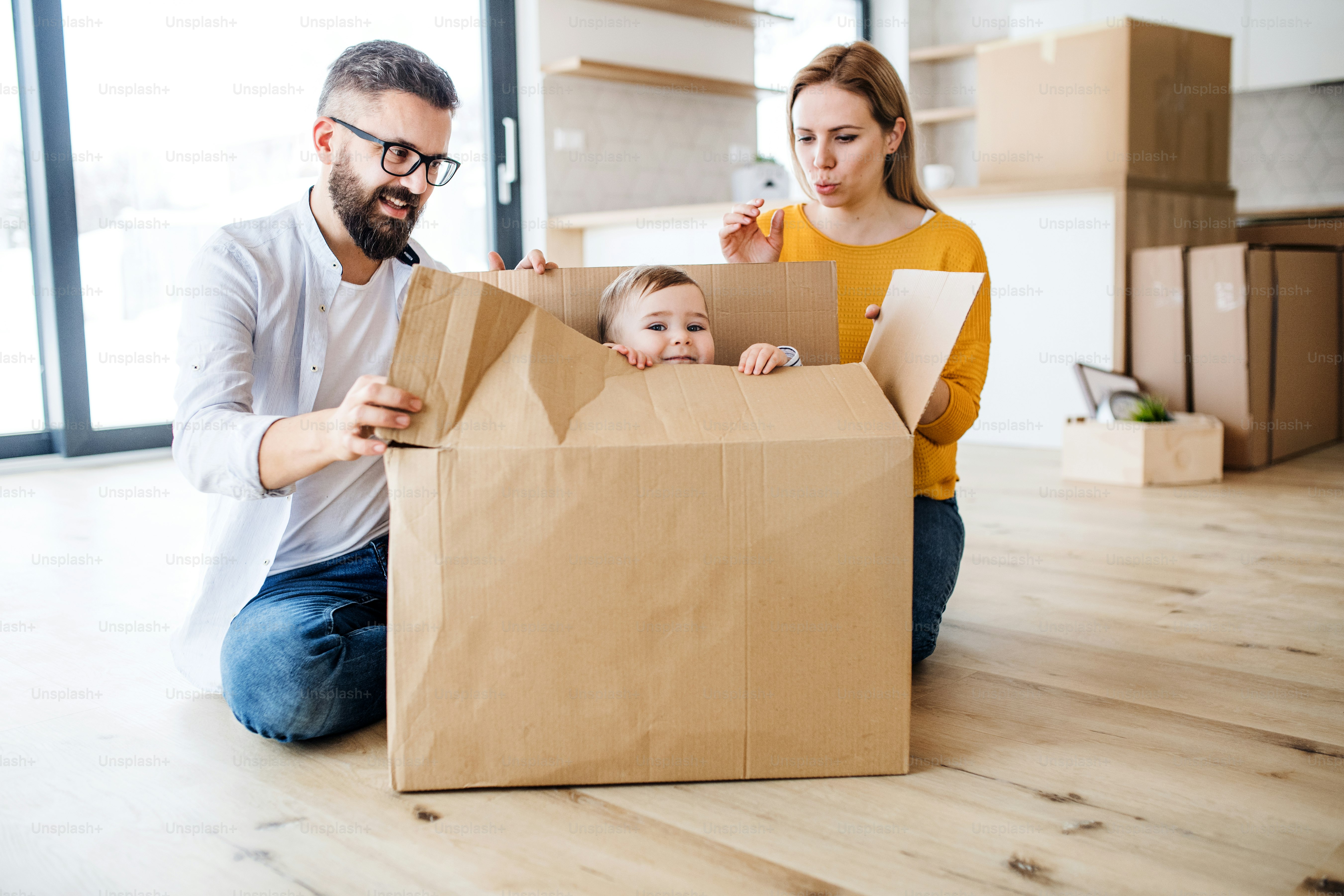 A portrait of happy young family with a toddler girl moving in new home ...