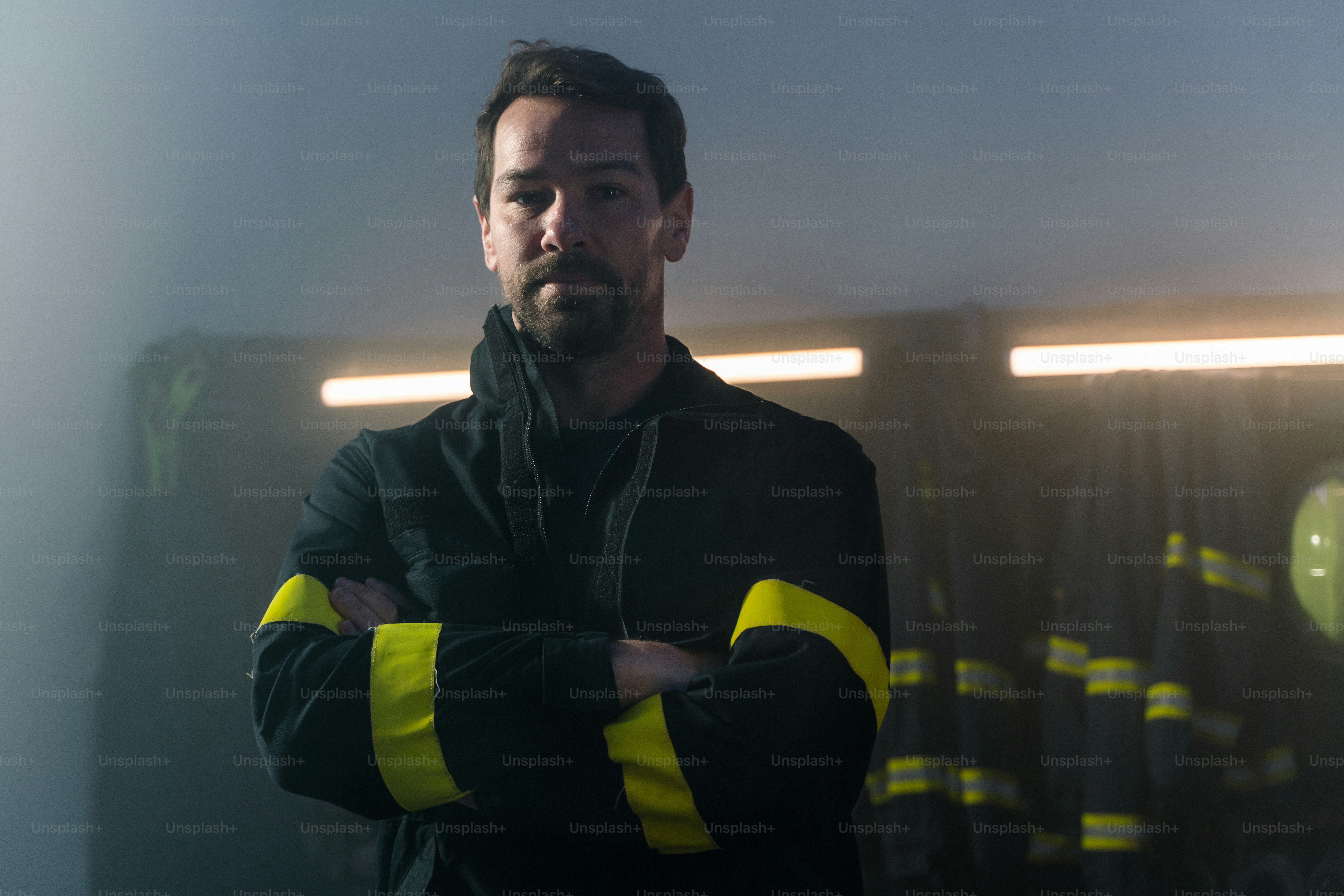 A mature firefighter in fire station at night, looking at camera. photo ...