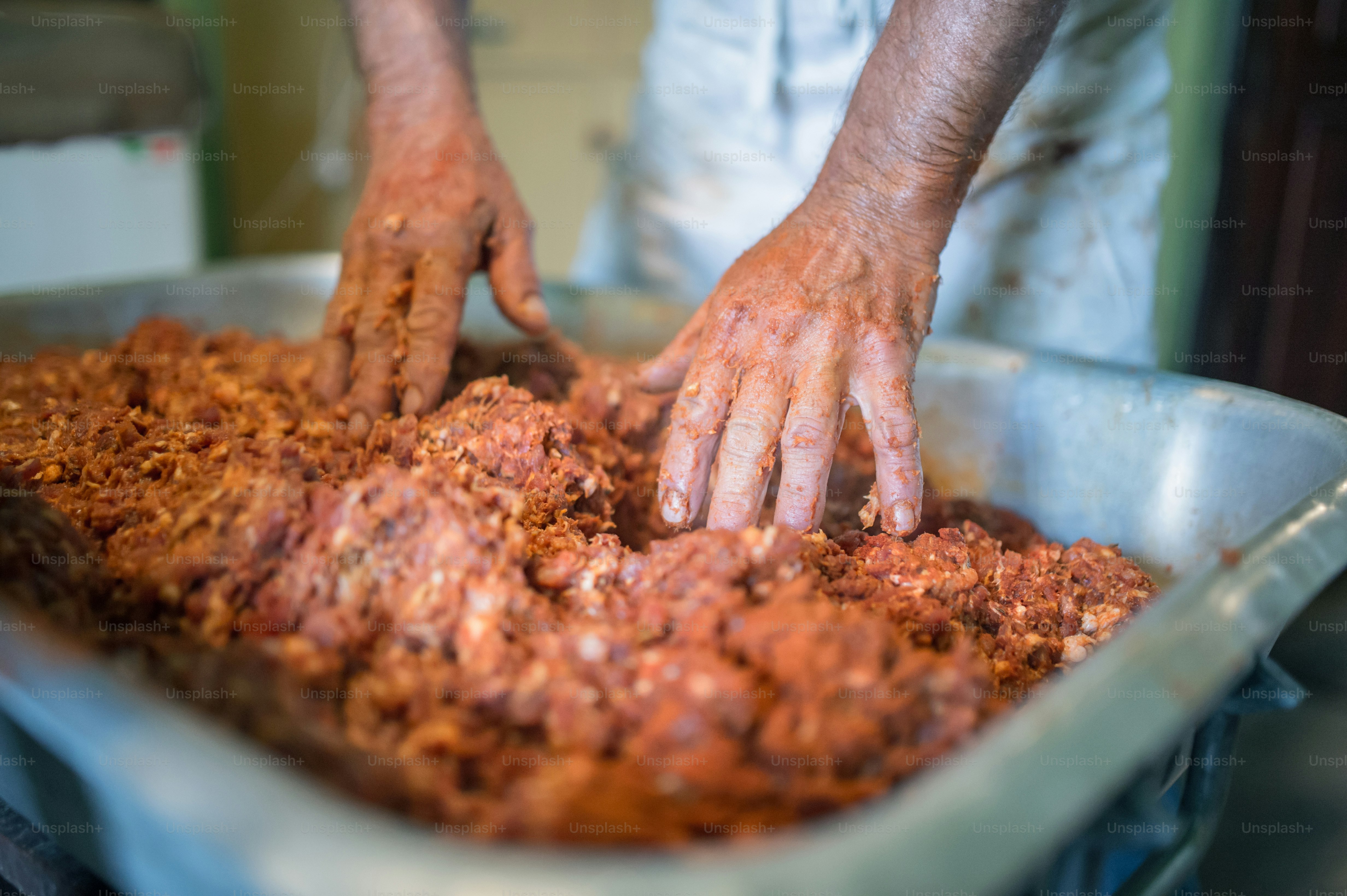 Unrecognizable man making sausages the traditional way at home. Mixing ...