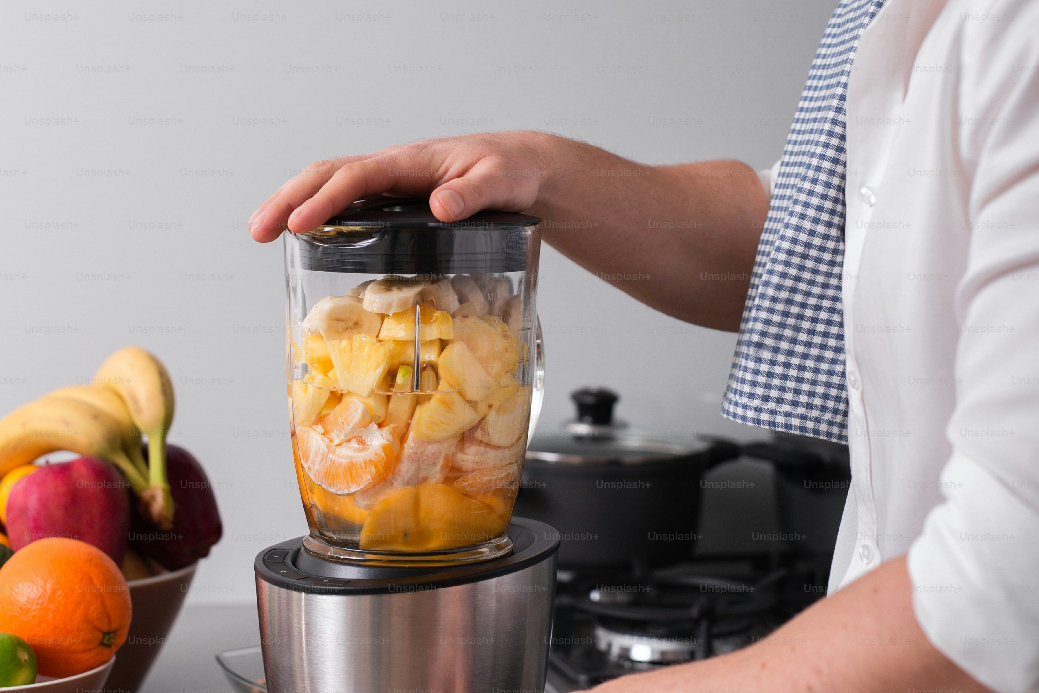 A close up cropped shot of man making smoothie from fresh fruits in ...