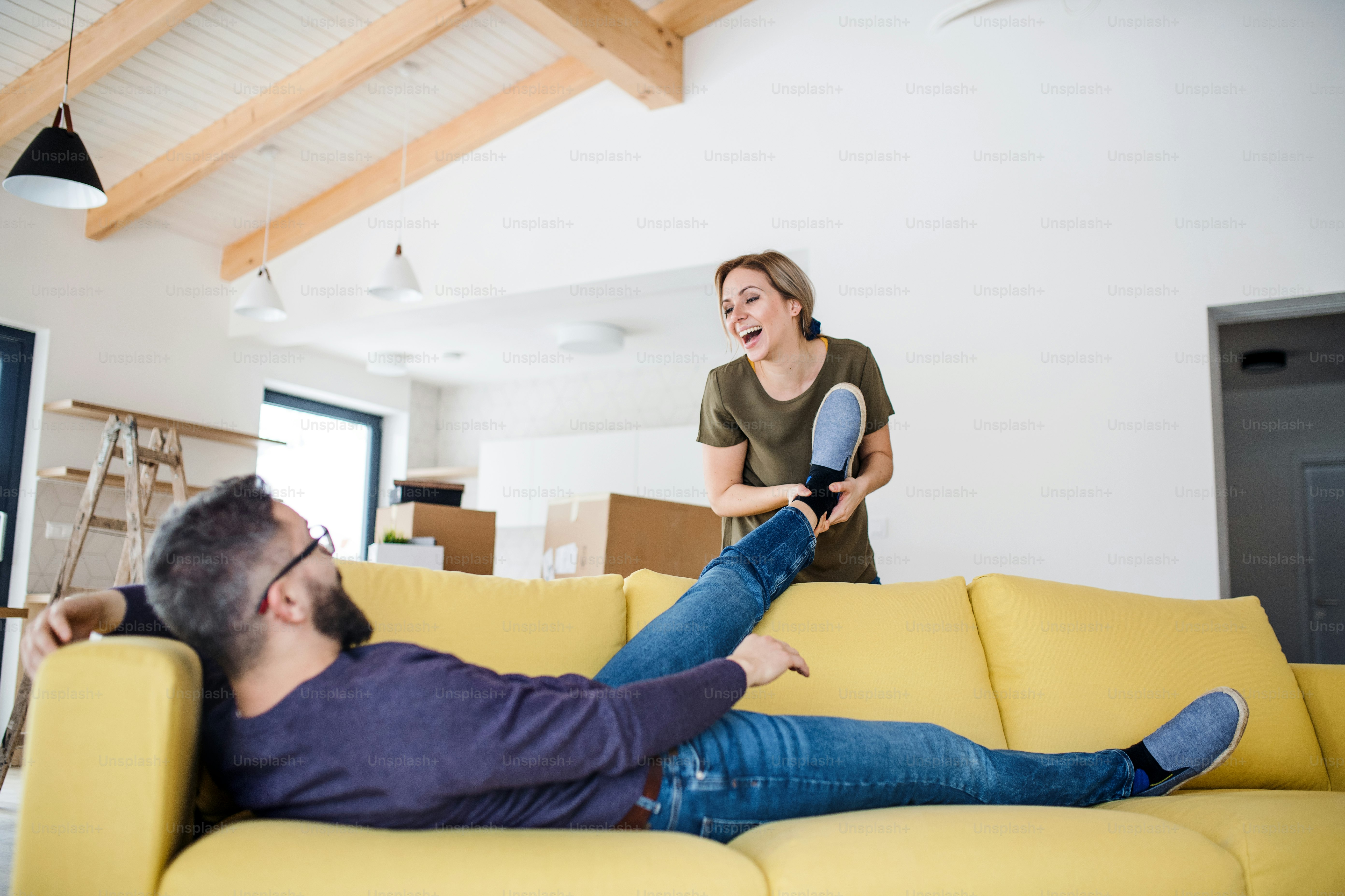 A young happy couple furnishing new house, having fun. A moving in new ...