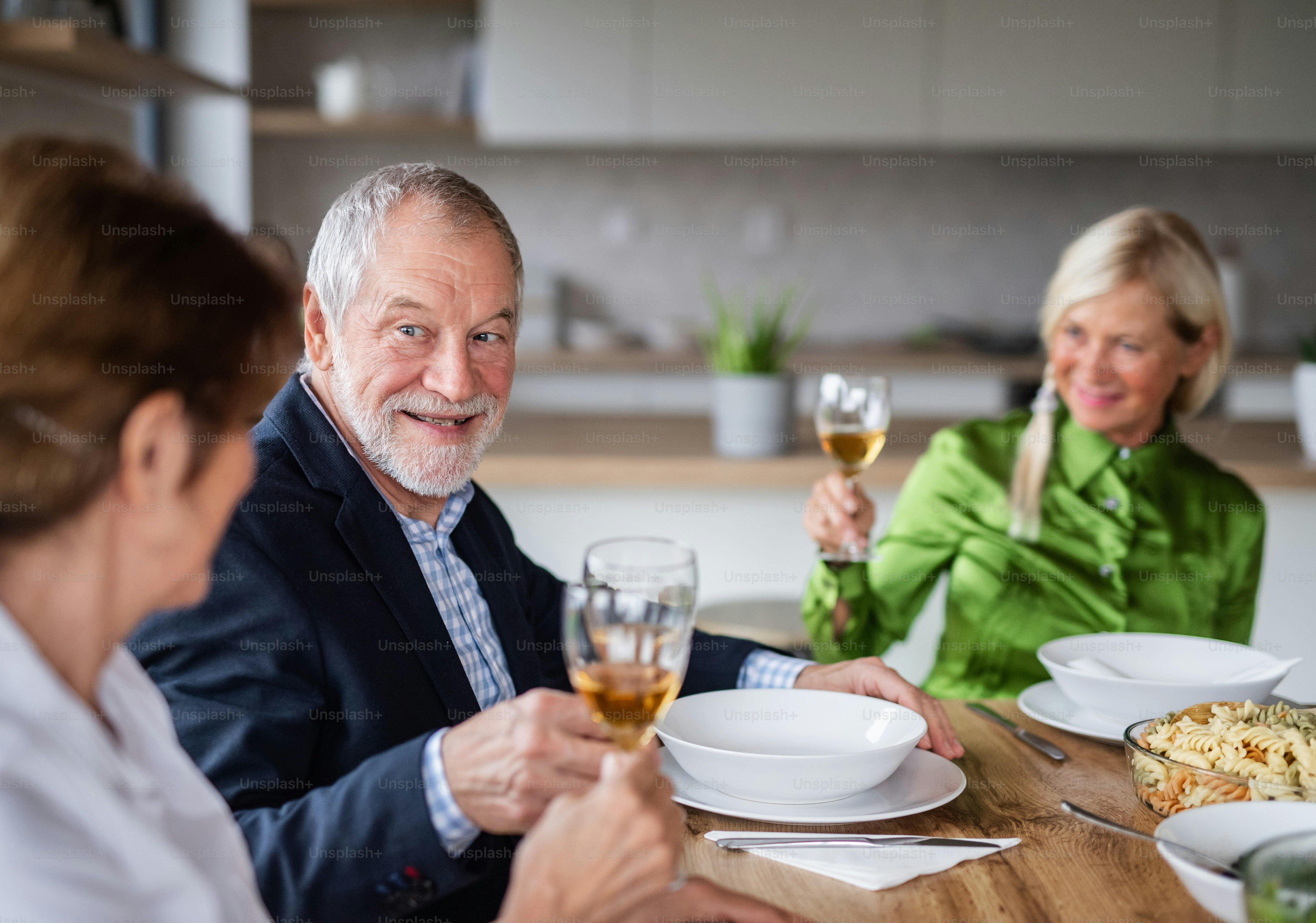 Group of cheerful senior friends at dinner party at home, with glasses ...