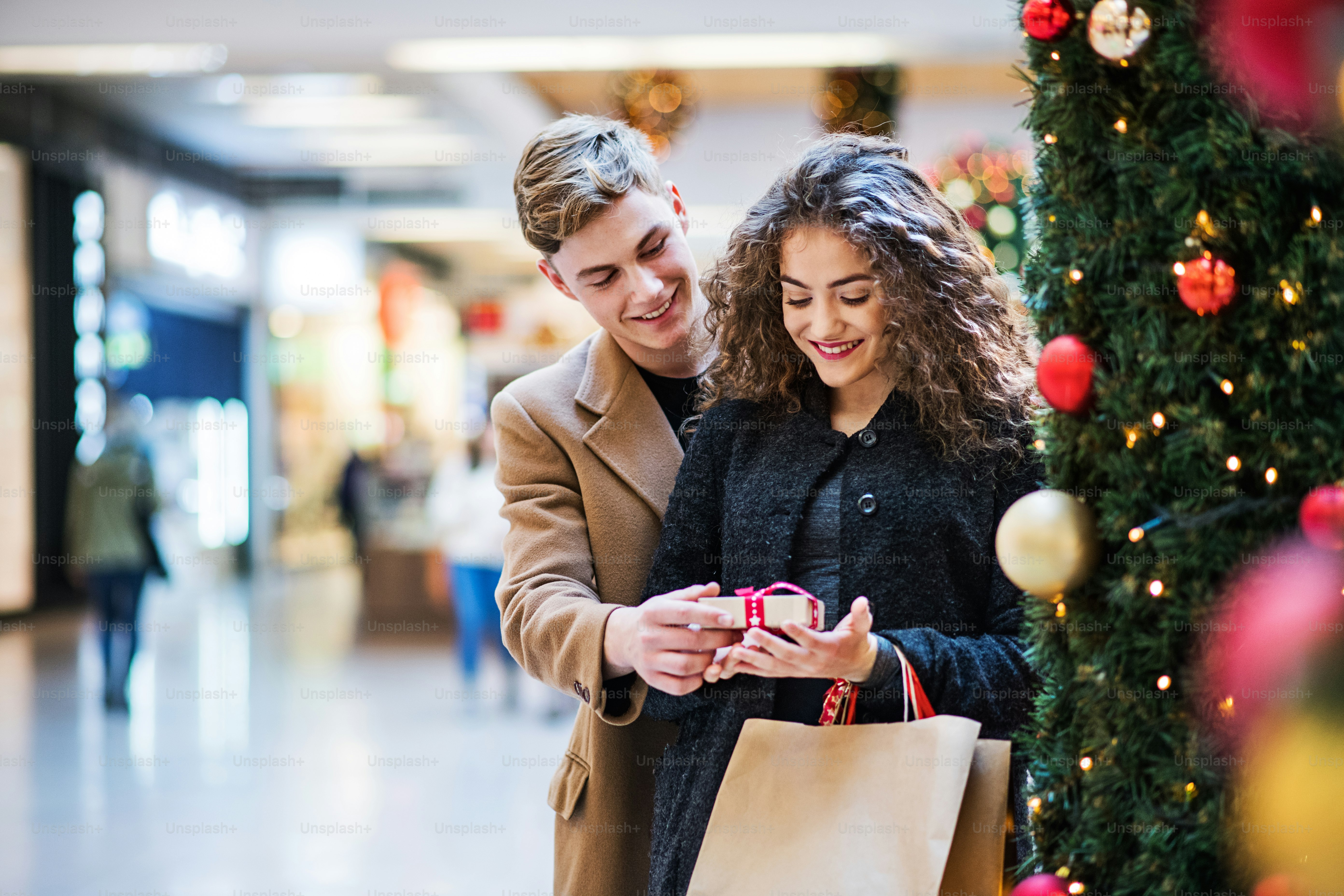 A happy young man giving a present to his girfriend in shopping center ...