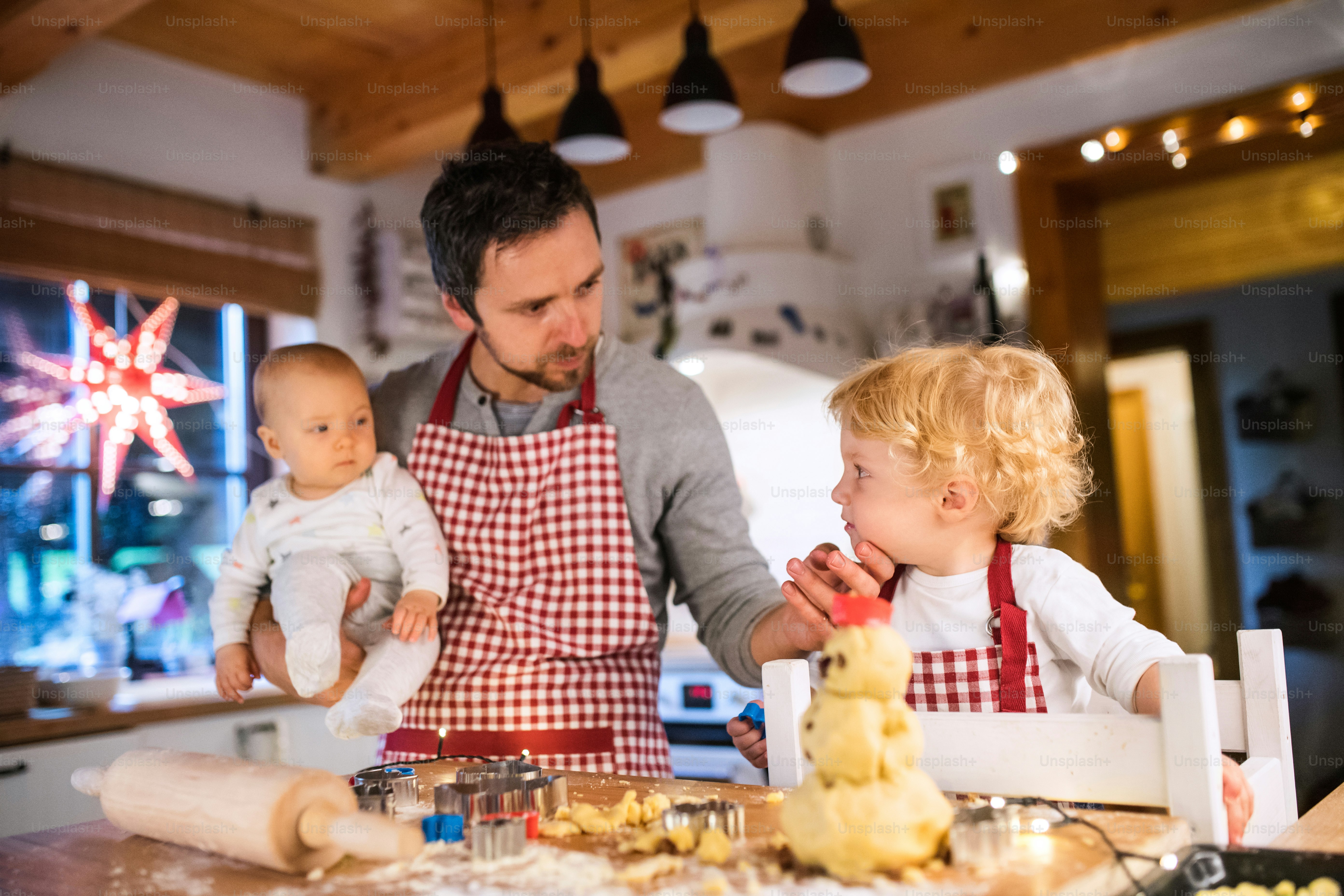 Man with a baby and a toddler boy making cookies at home. Father and ...