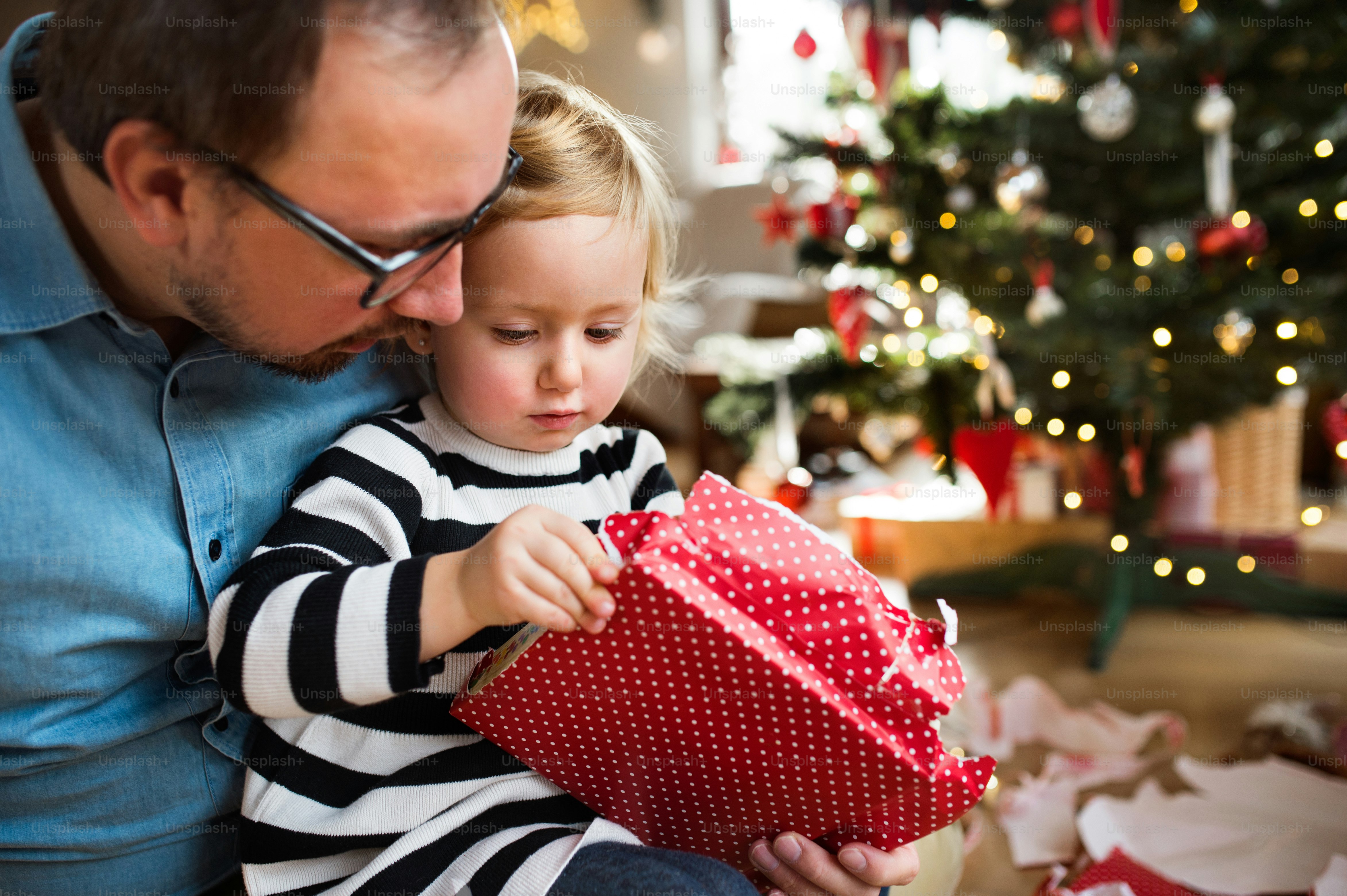 Beautiful little girl with her father opening Christmas present. photo ...