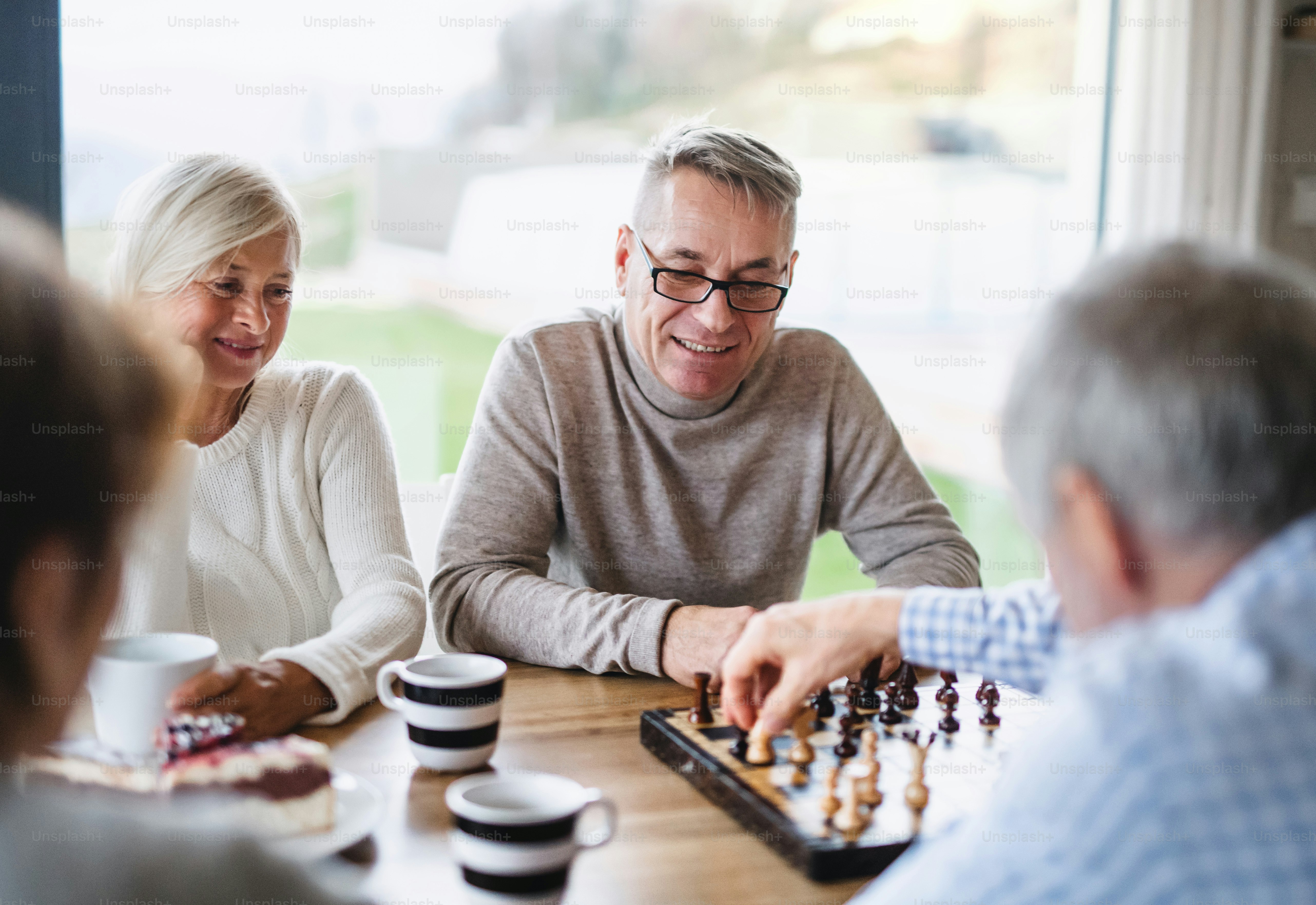 Group of cheerful senior friends at home, playing board games. photo ...