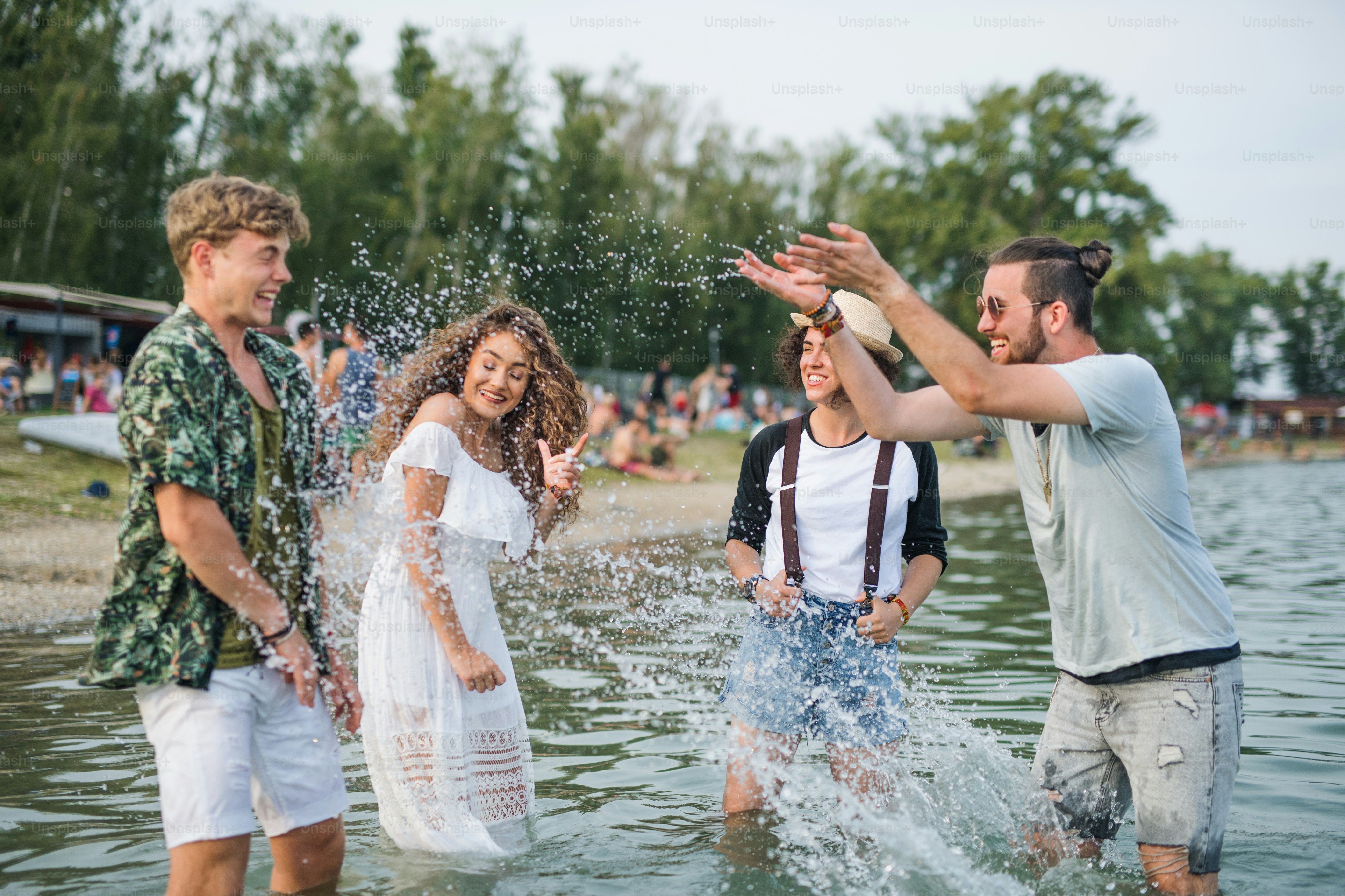 Group of young friends at summer festival, standing in lake and ...