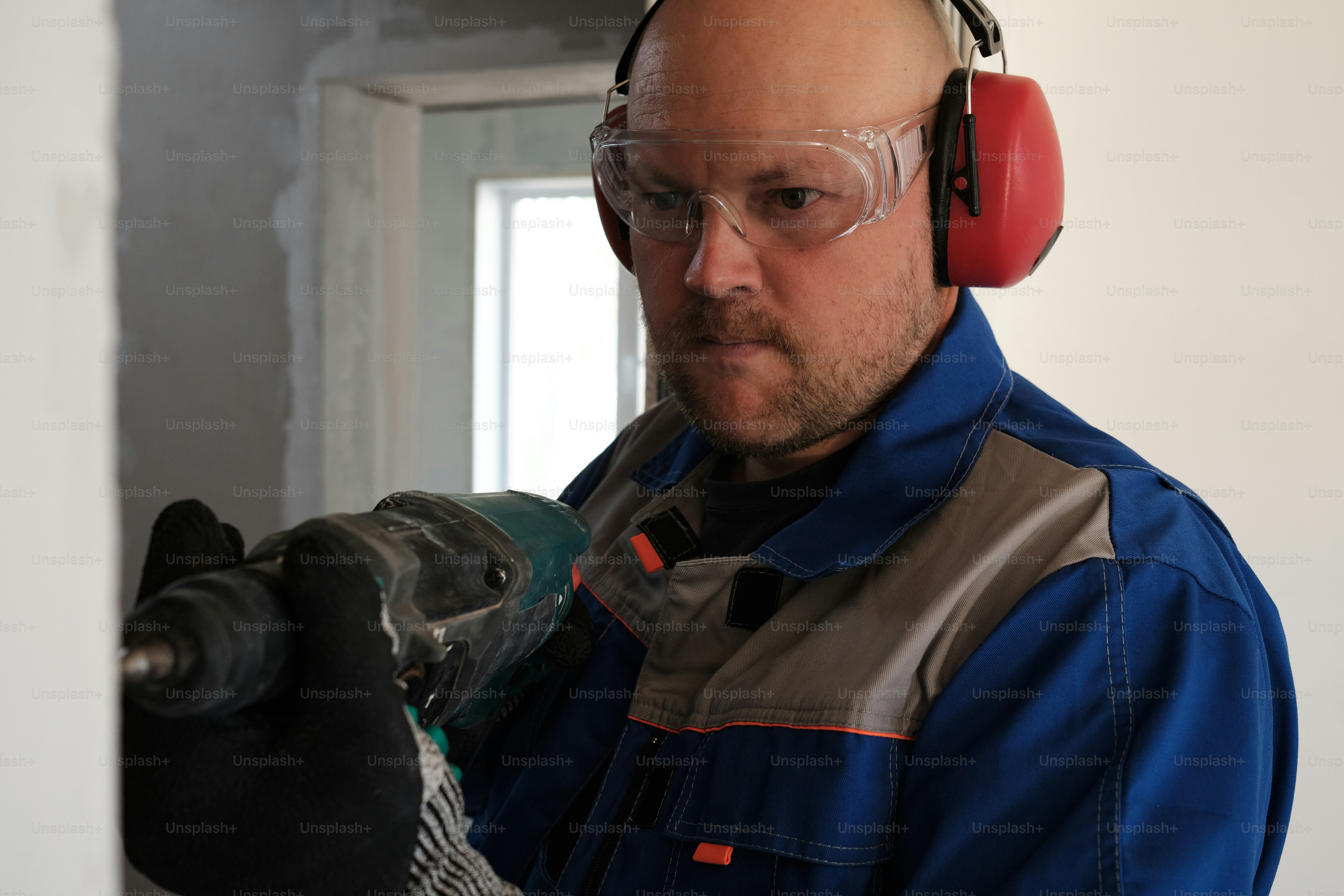 A man wearing safety goggles holding a drill photo – Renovation Image ...