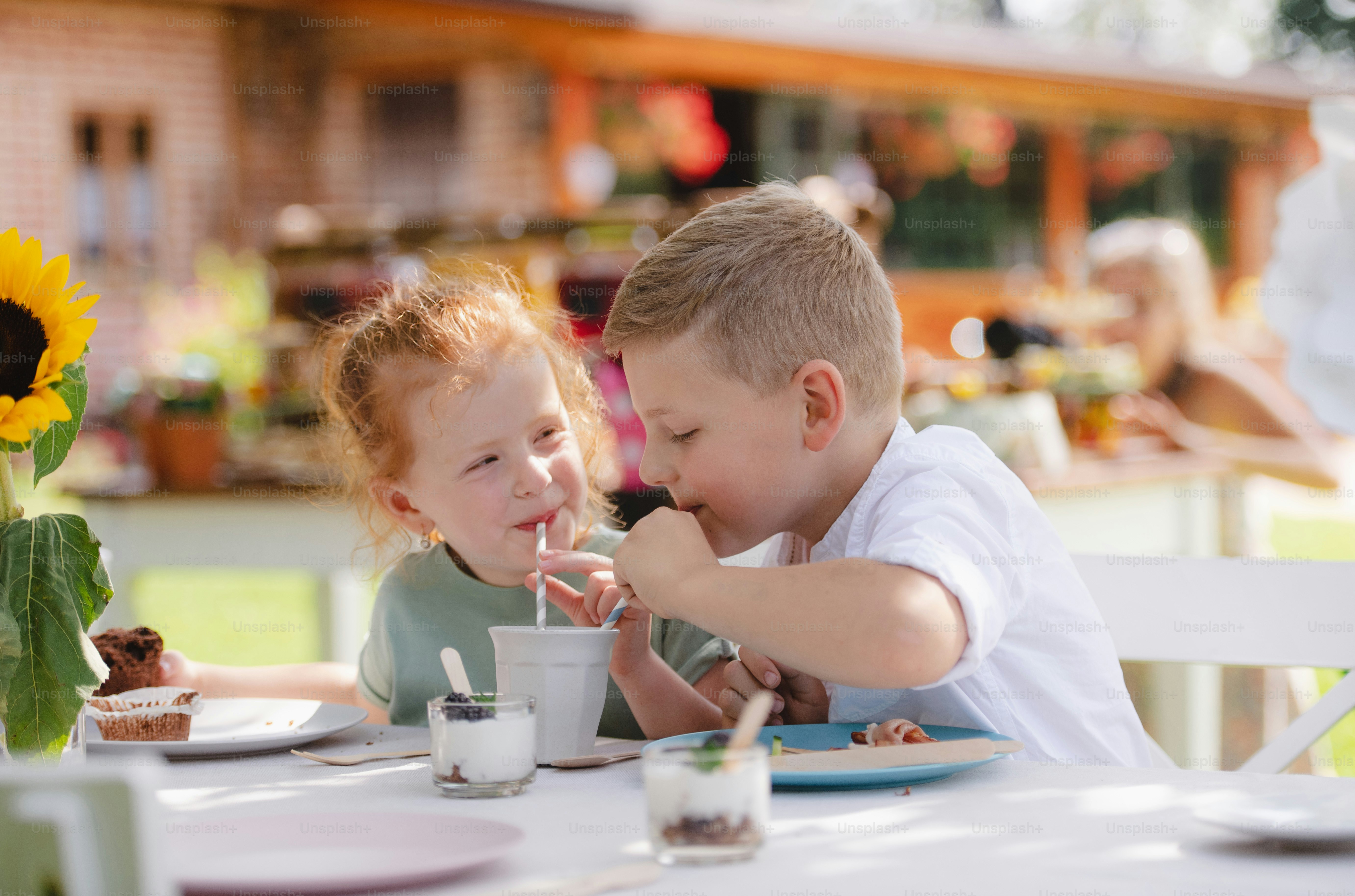 Grupo de niños pequeños sentados a la mesa al aire libre en una fiesta ...