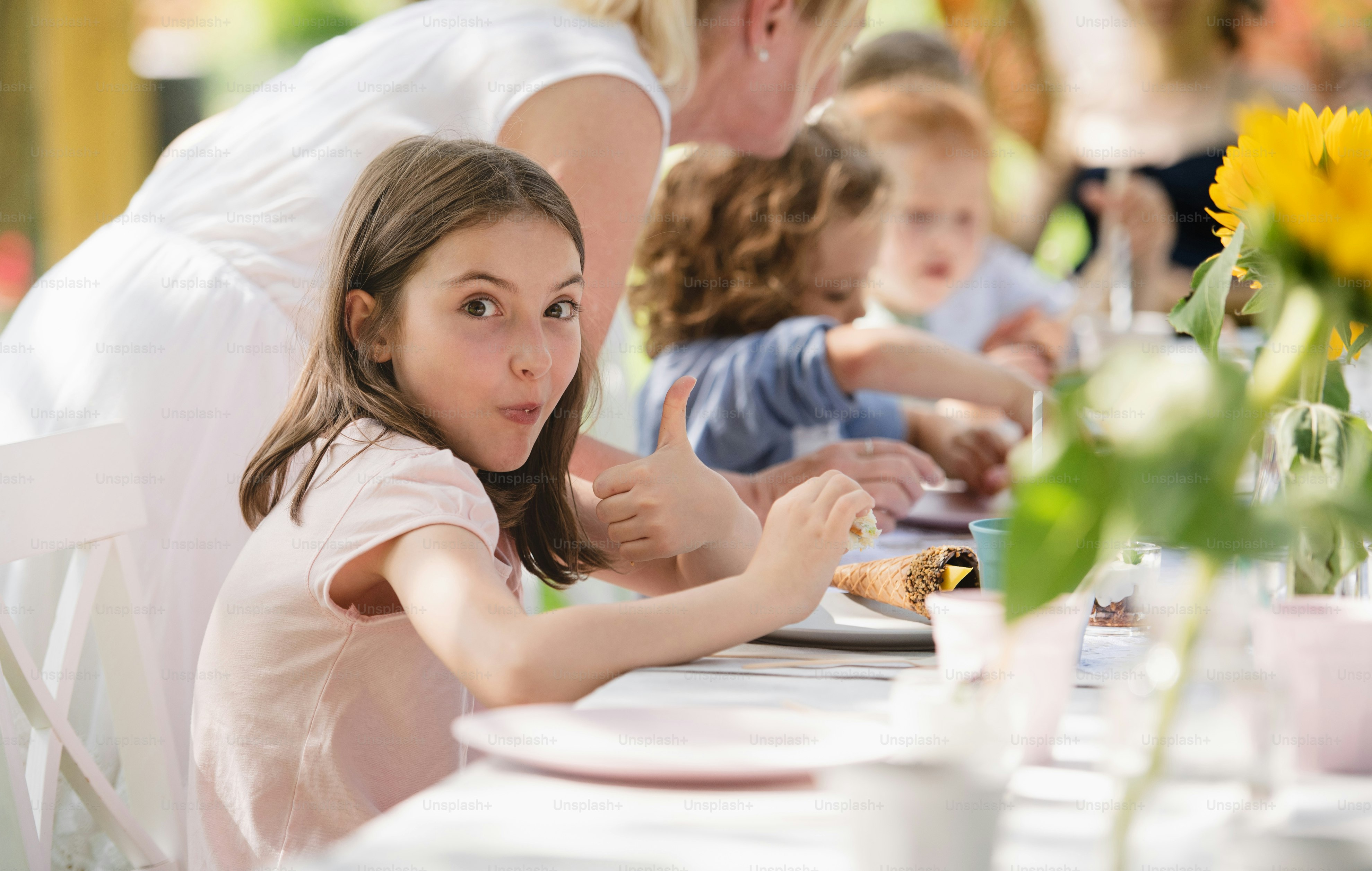 Group of small children sitting at the table outdoors on garden party ...