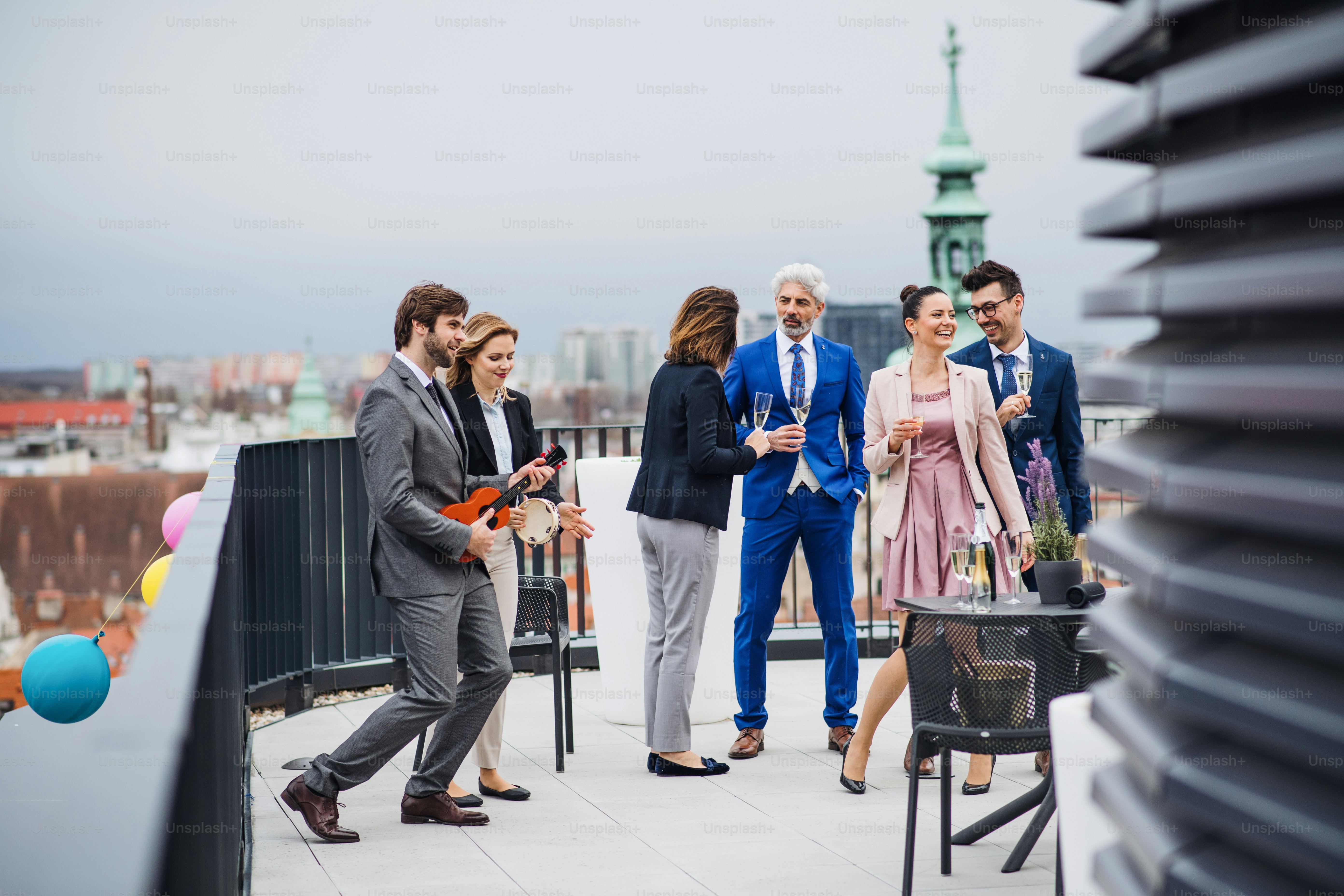 A large group of joyful businesspeople having a party outdoors on roof ...