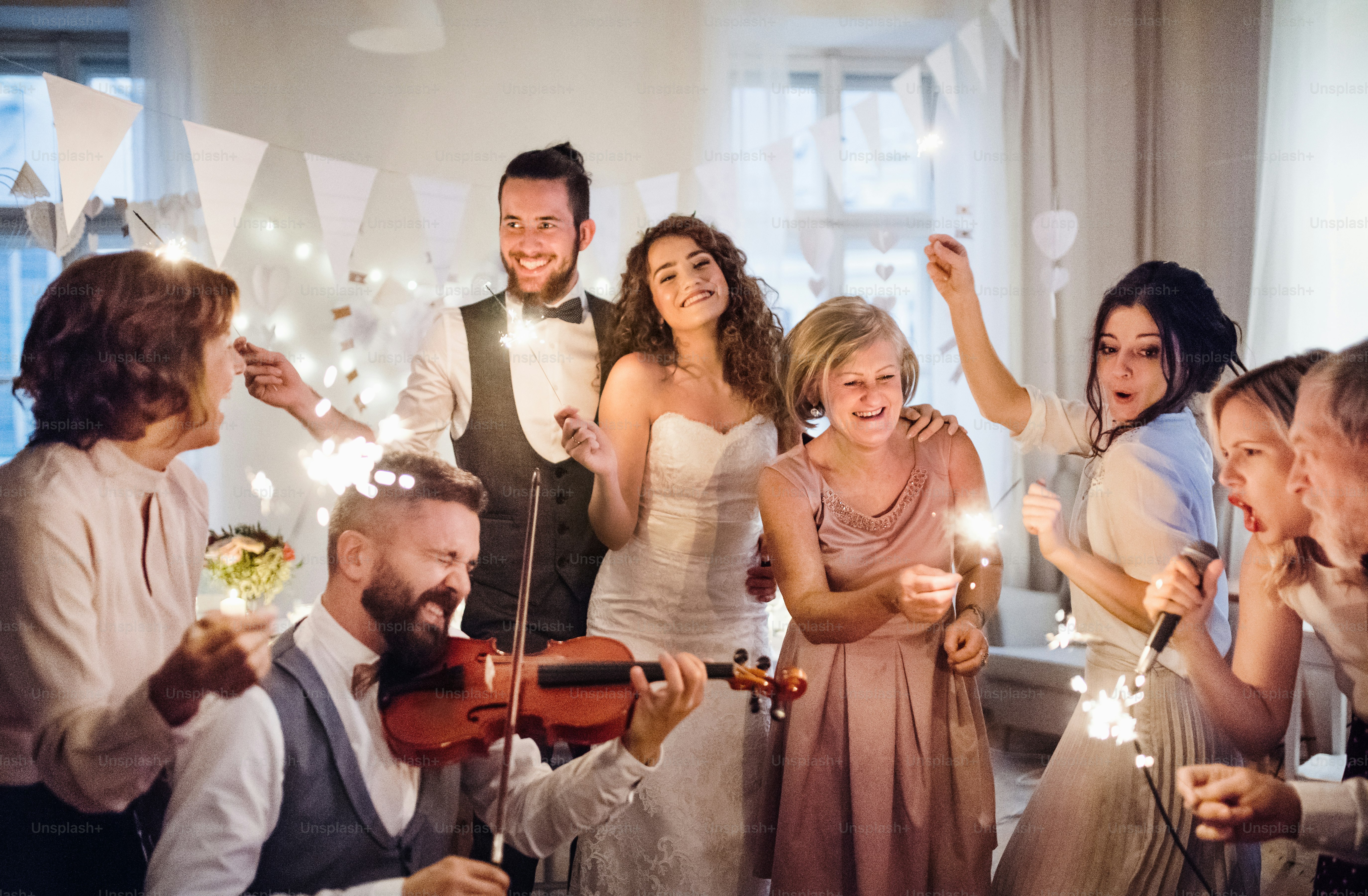 A young cheerful bride, groom and other guests dancing, singing and ...