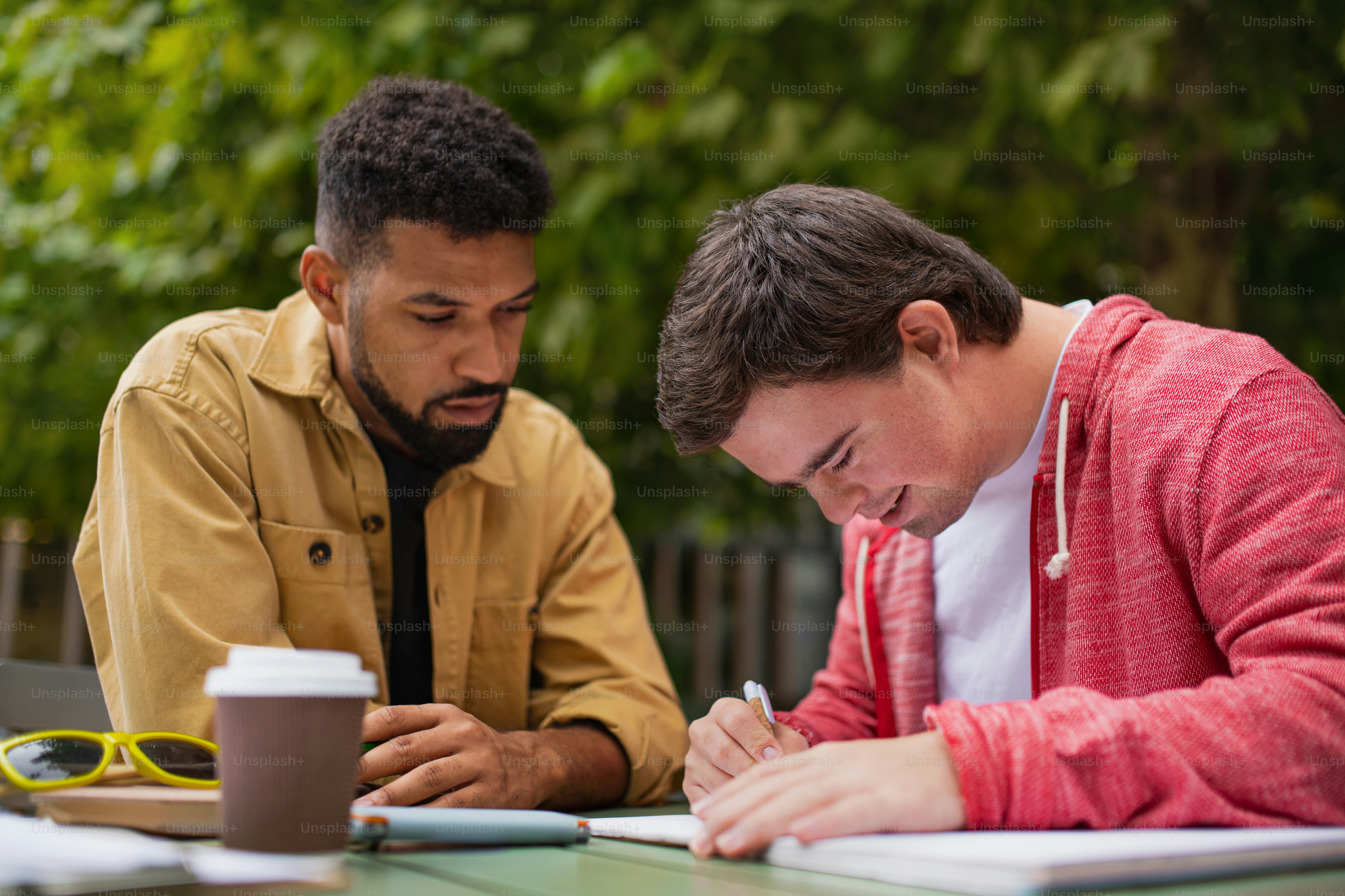 A young man with Down syndrome with his mentoring friend sitting ...