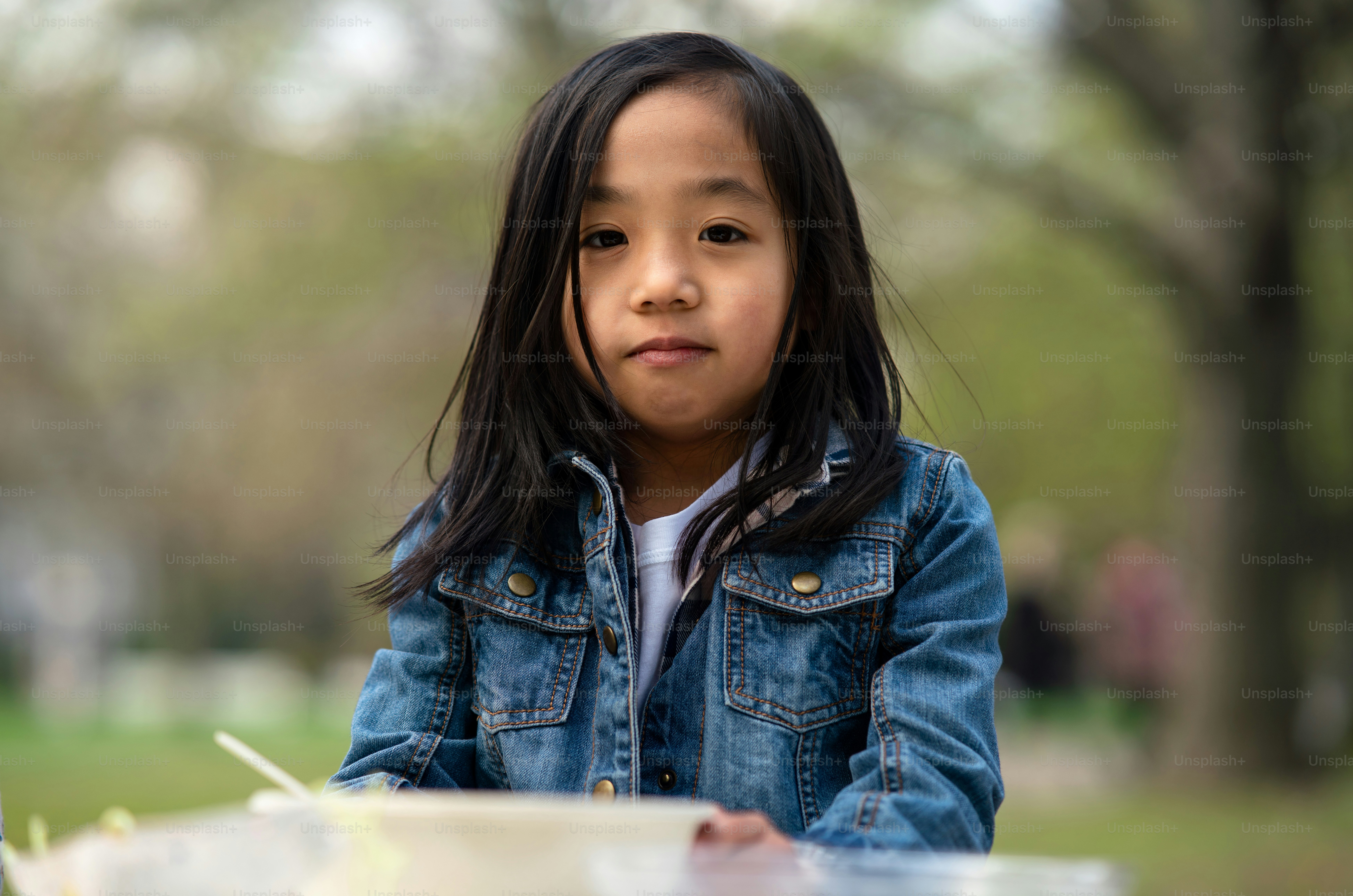 Portrait of small child looking at camera outdoors in city park ...