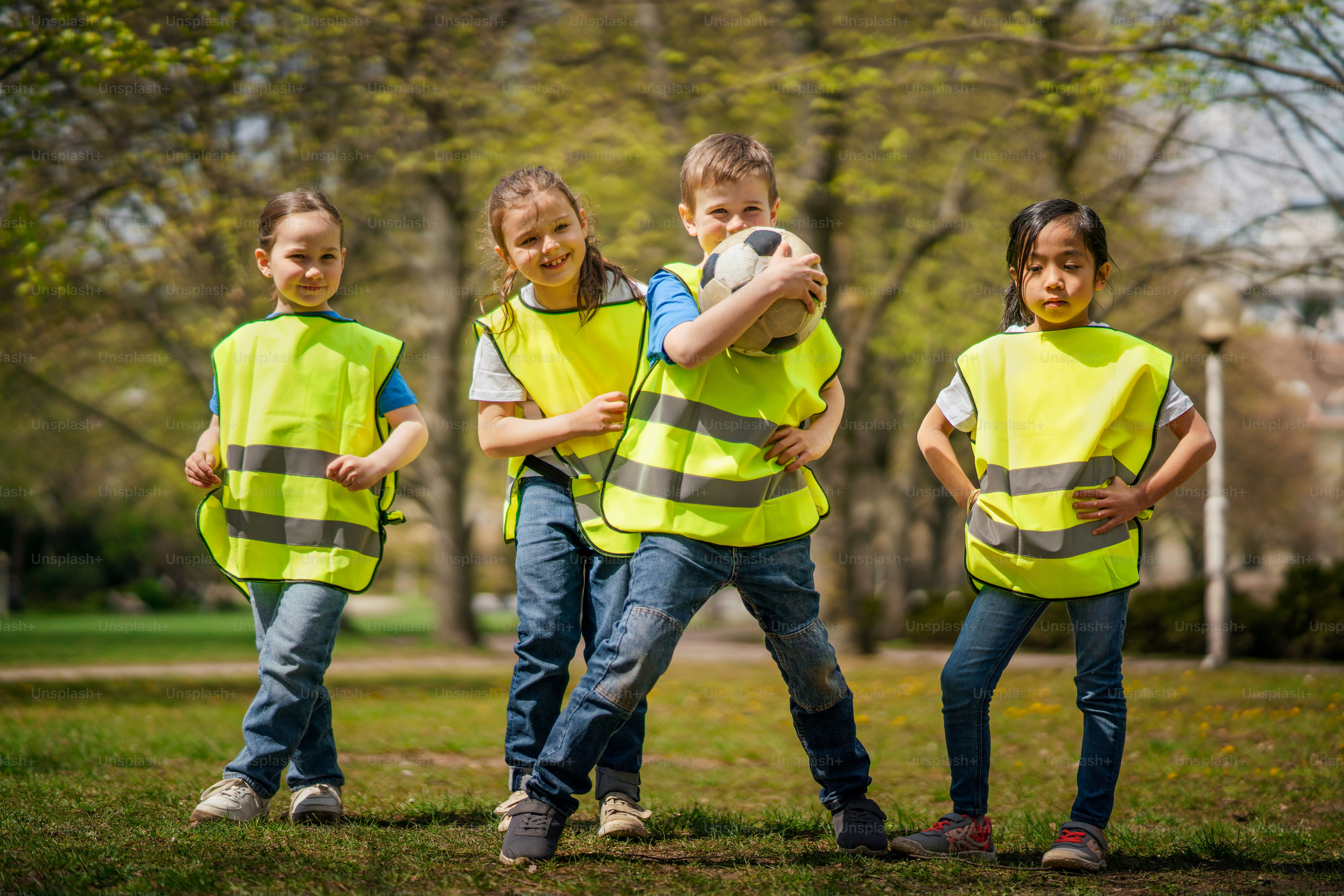 A small children with ball looking at camera outdoors in city park ...