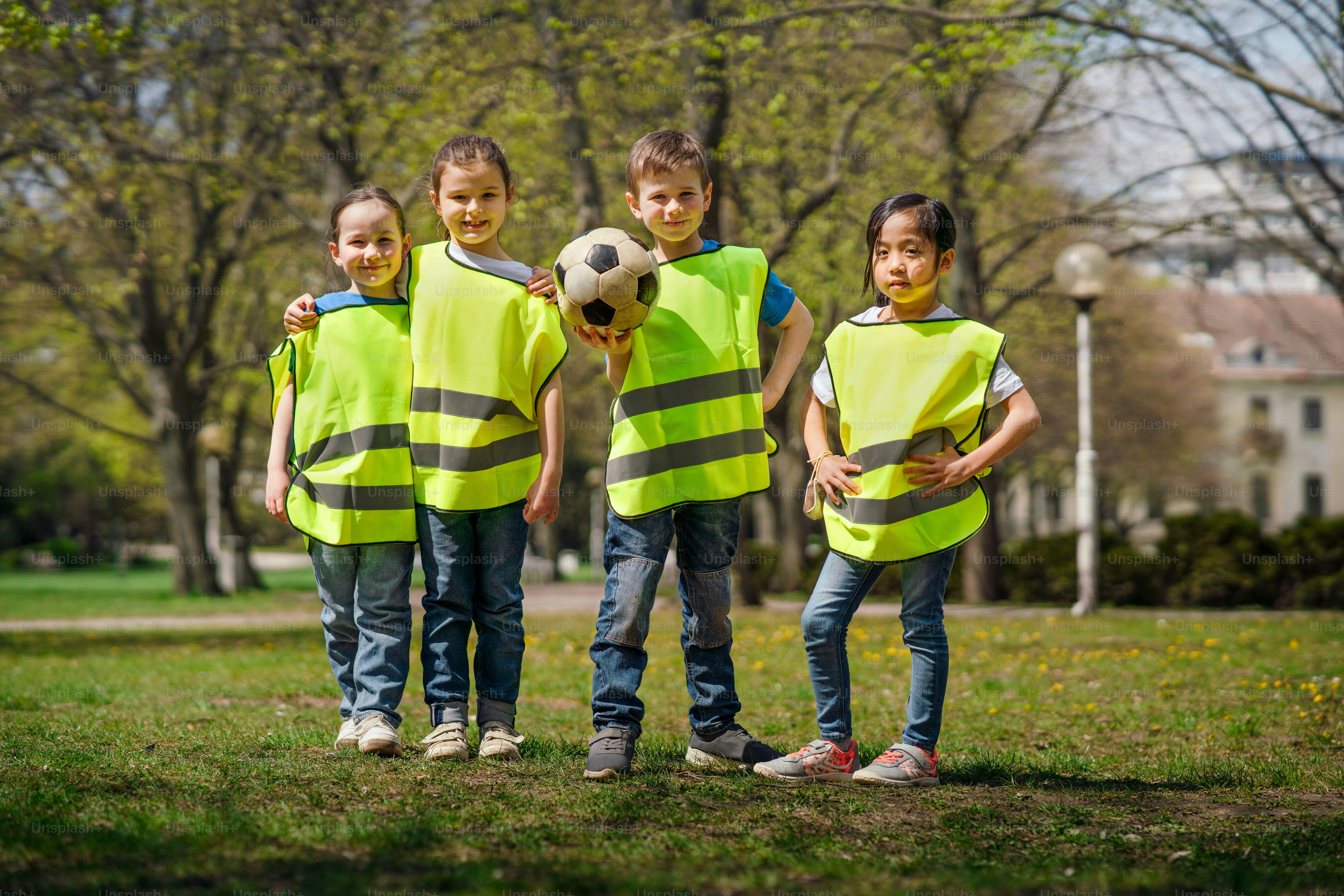 Happy small children playing football outdoors in city park, learning ...