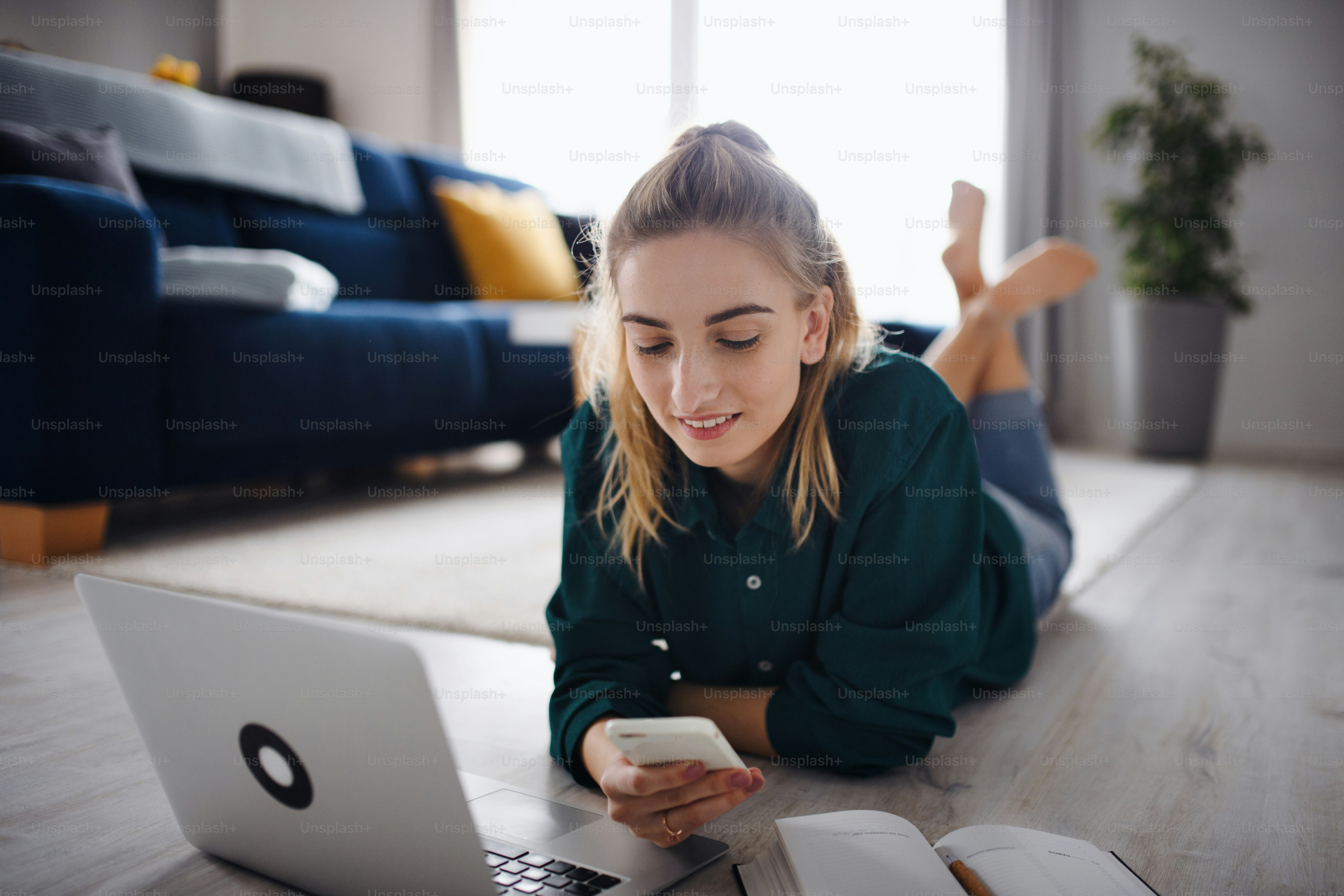 A young woman student with laptop and smartphone at home, home office ...
